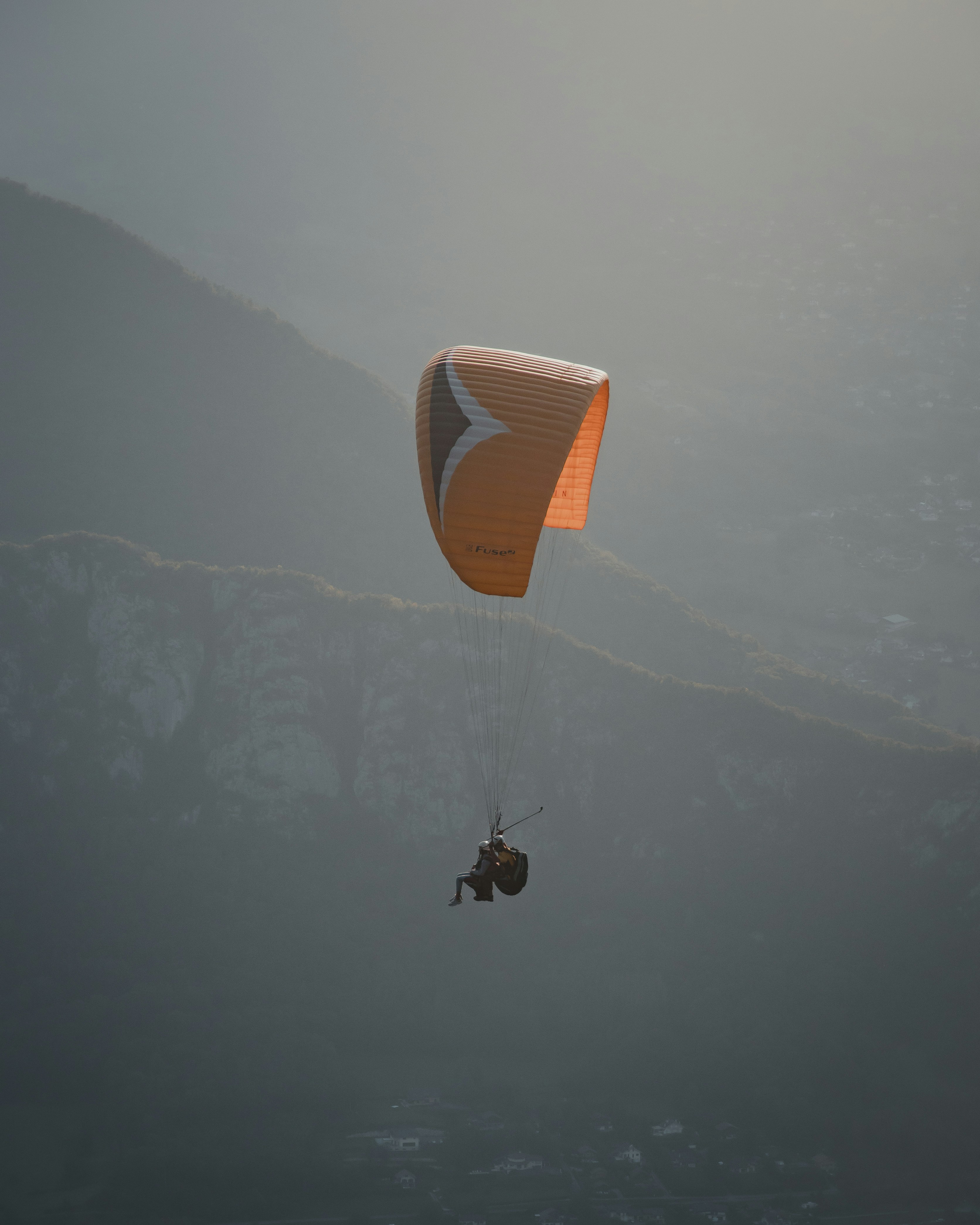 A paraglider gracefully descends against a backdrop of misty mountains, showcasing the thrill of aerial adventure.