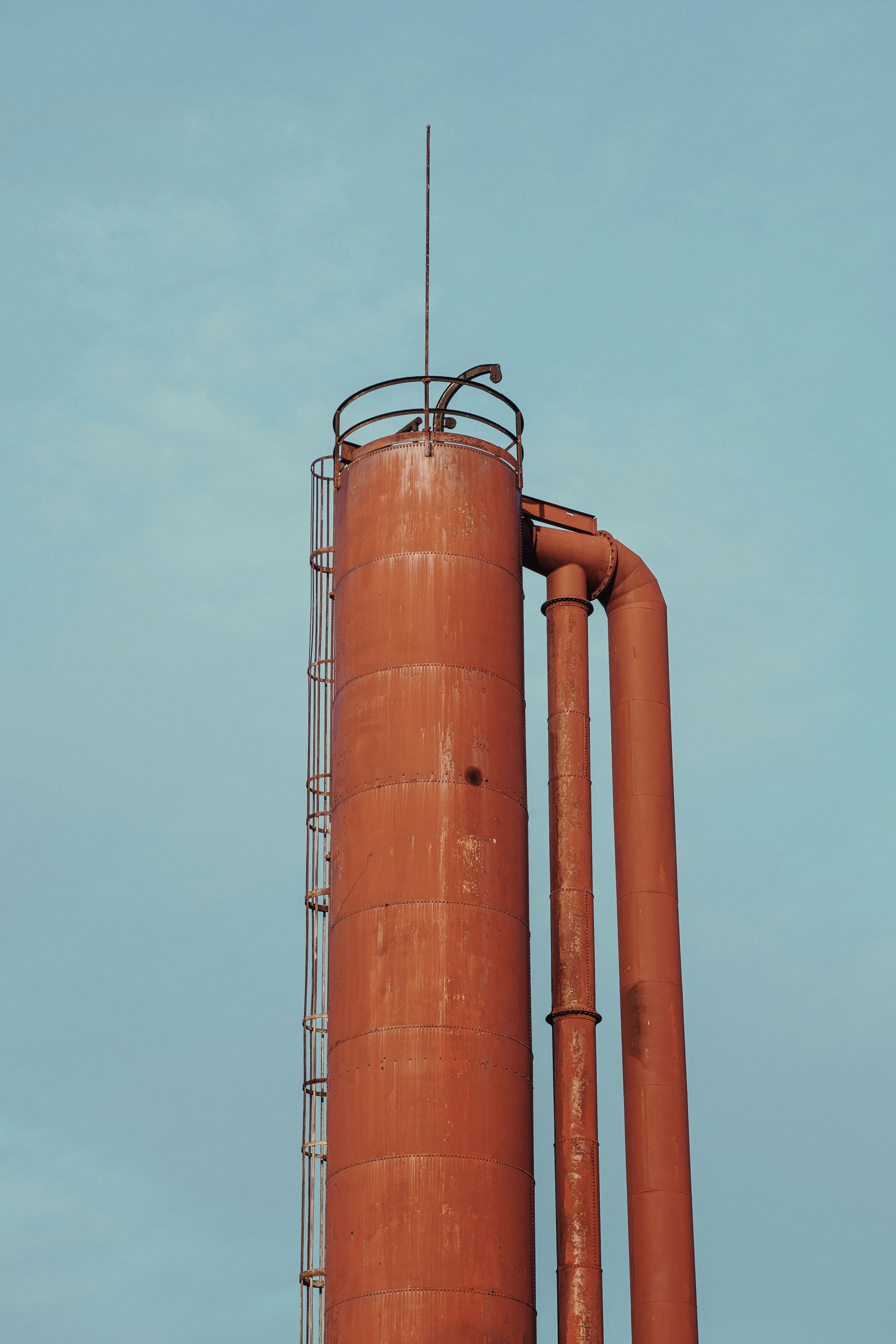 Rust-Red Silo with a Curved Pipe Against a Cerulean Sky