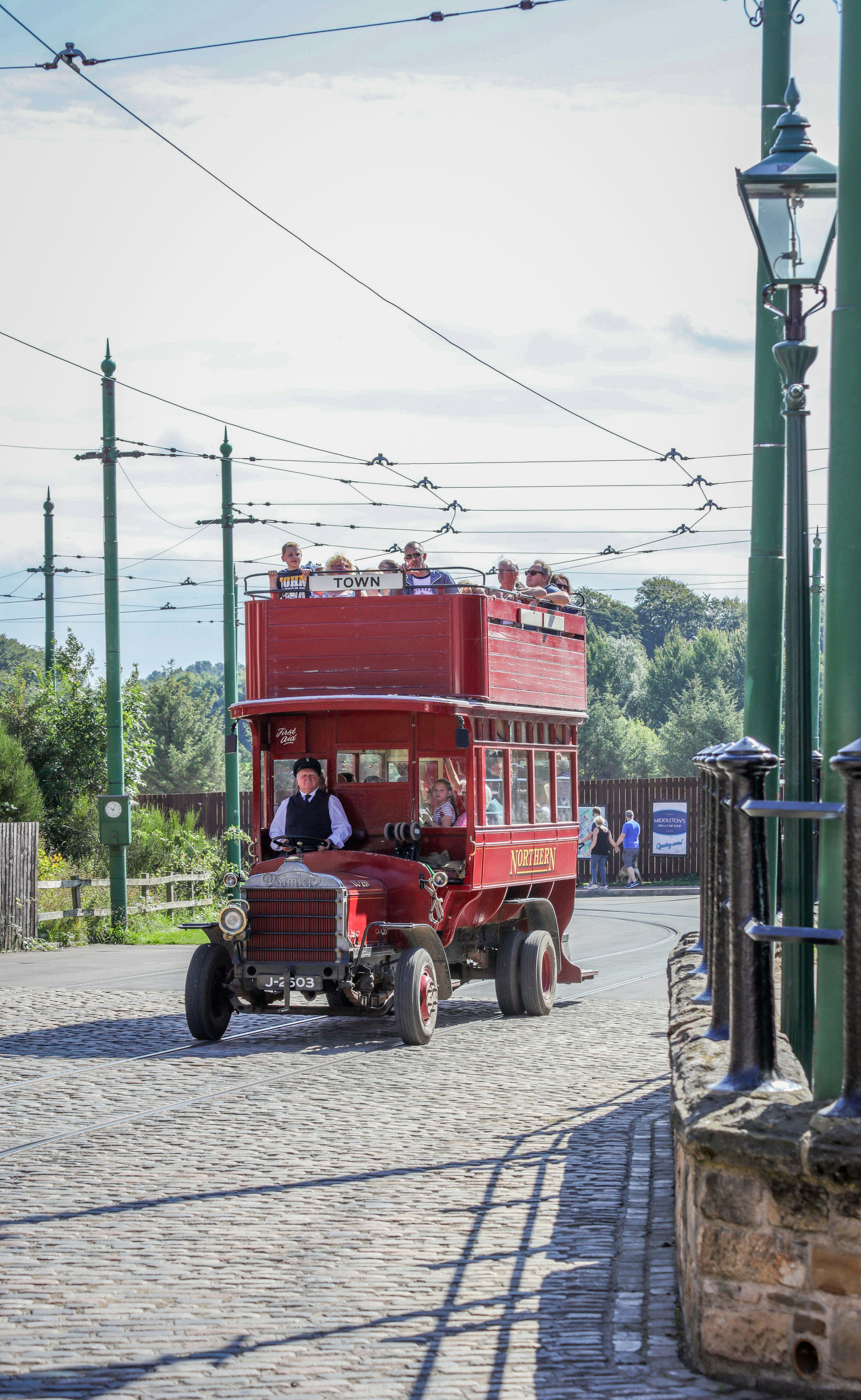 Vintage Tour: A Bright Red Double-Deck Bus Traverses a Cobblestone Street