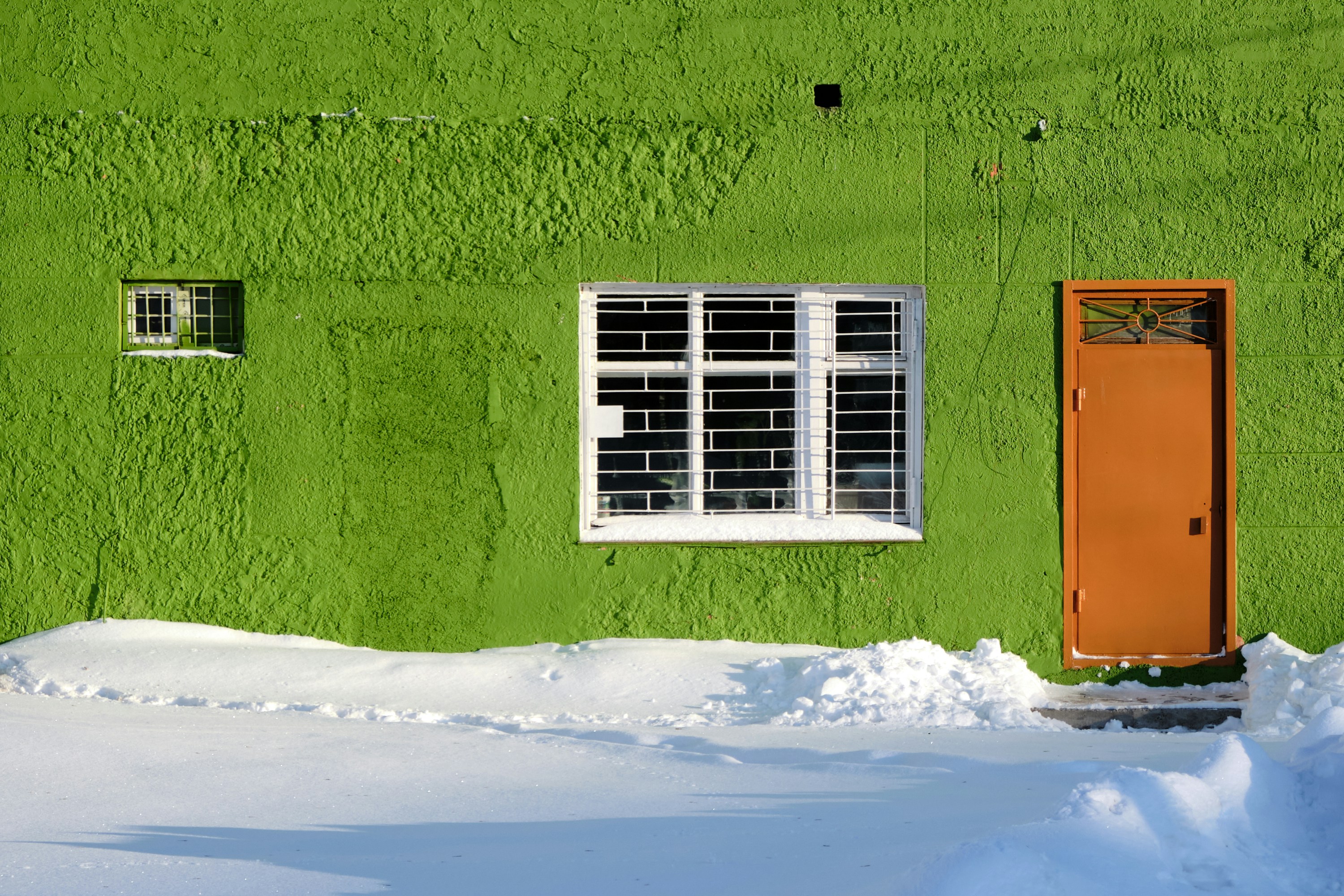 Emerald Facade with a Fiery Orange Door Under Winter Light