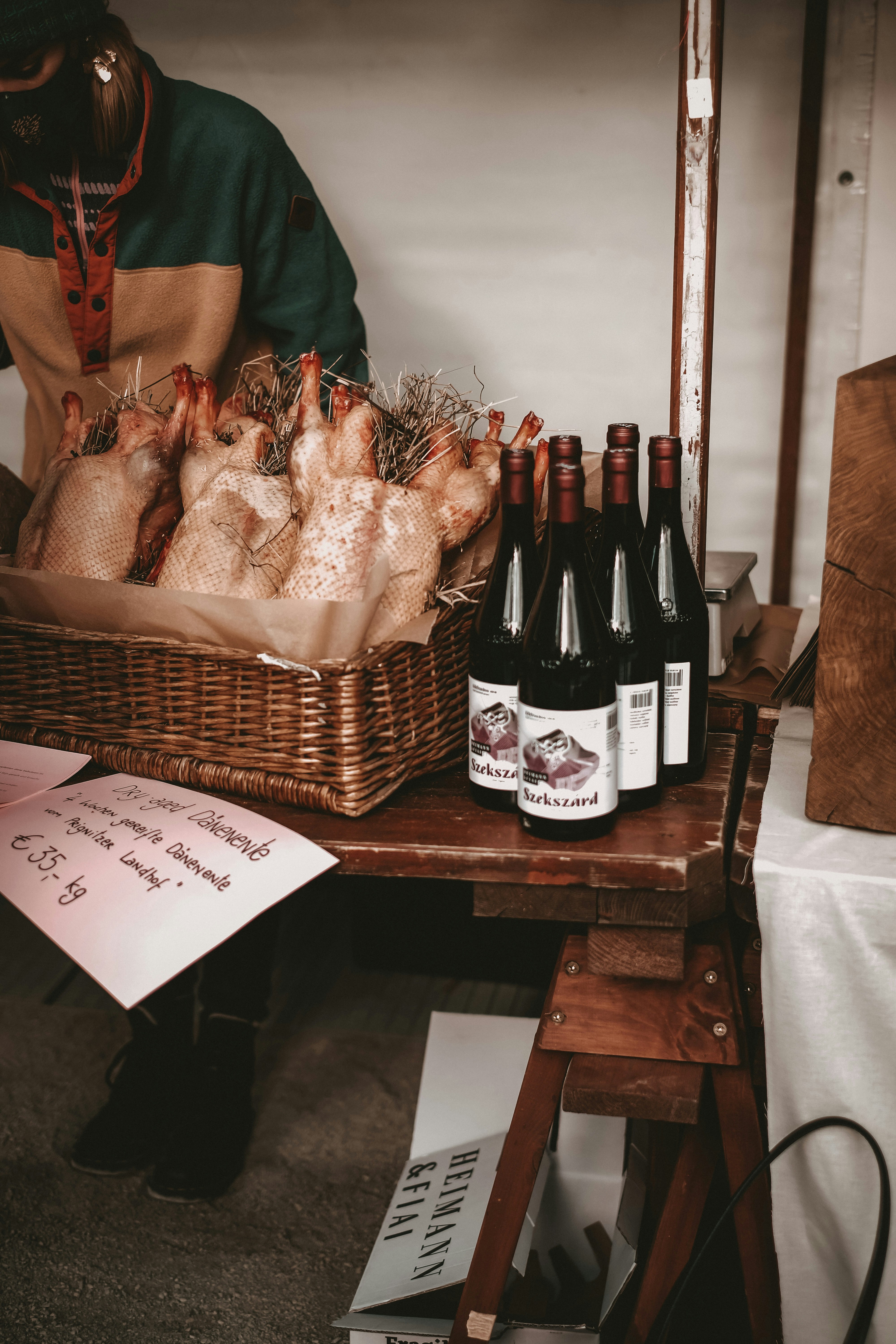 Wine Bottles Guard a Basket of Poultry at a Rustic Market Stall