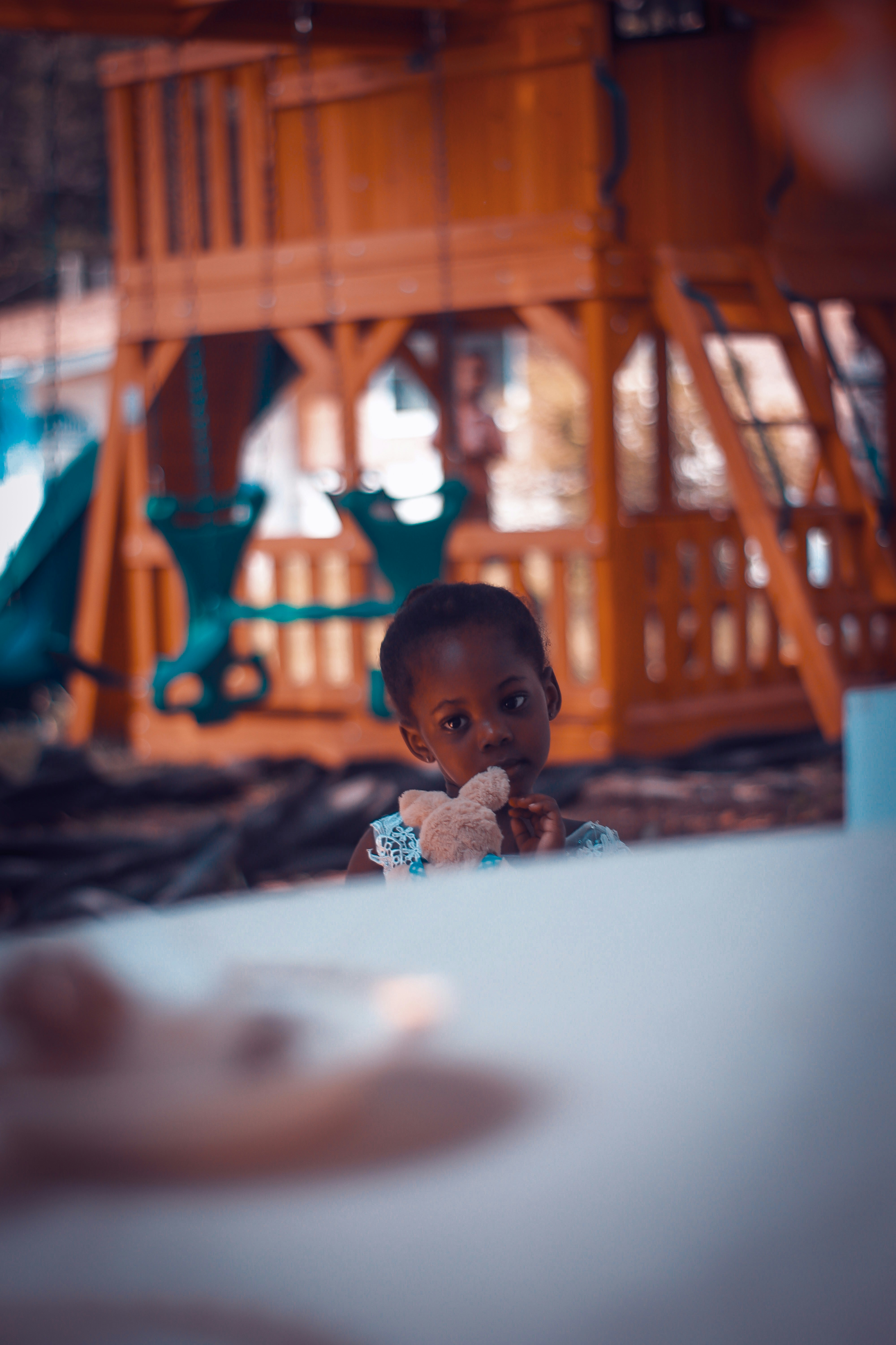 Soft-Gaze Under Cedar: A Child with Plush at a Wooden Playground