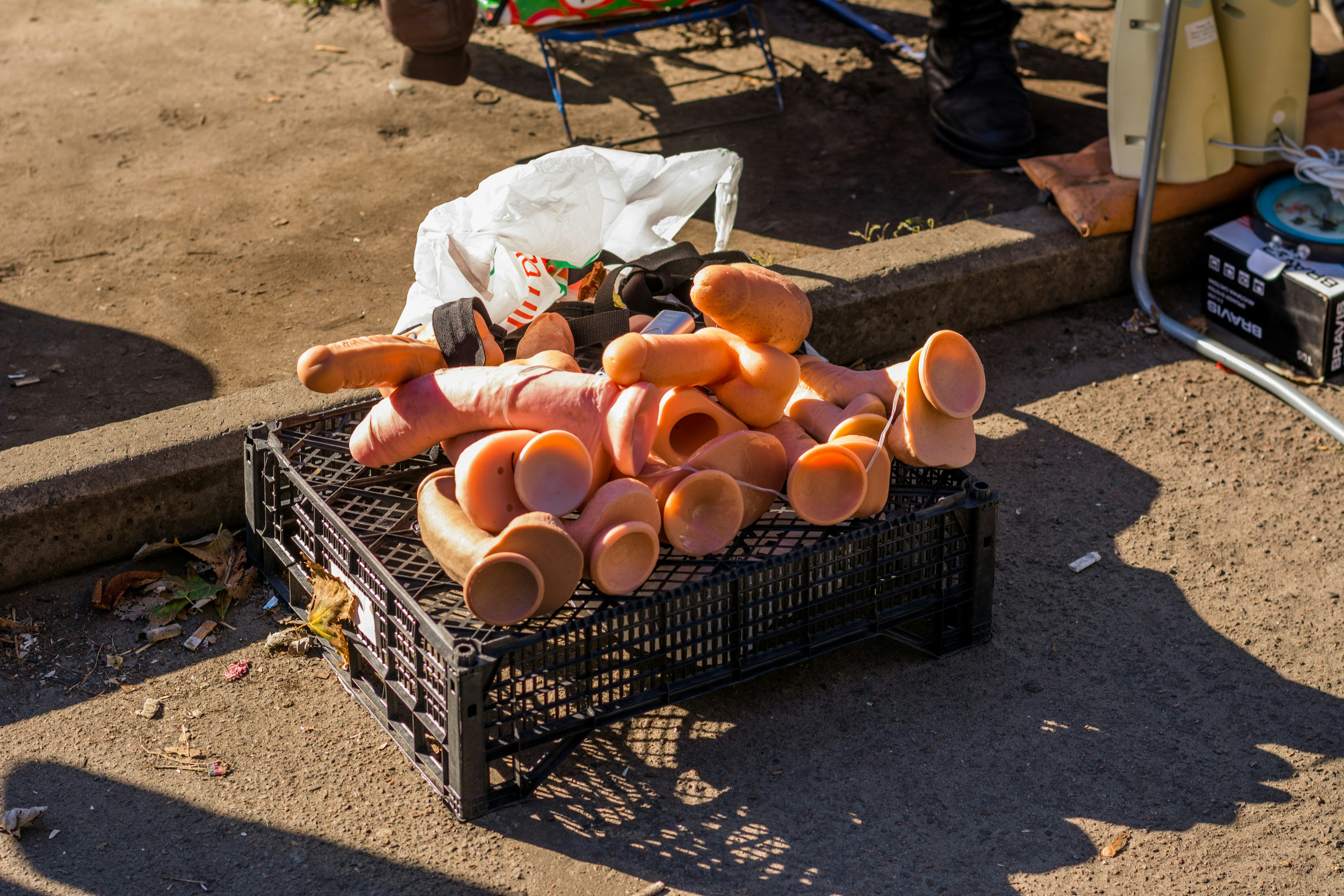 Orange-capped mushrooms spill from a crate at a sunlit street market stall