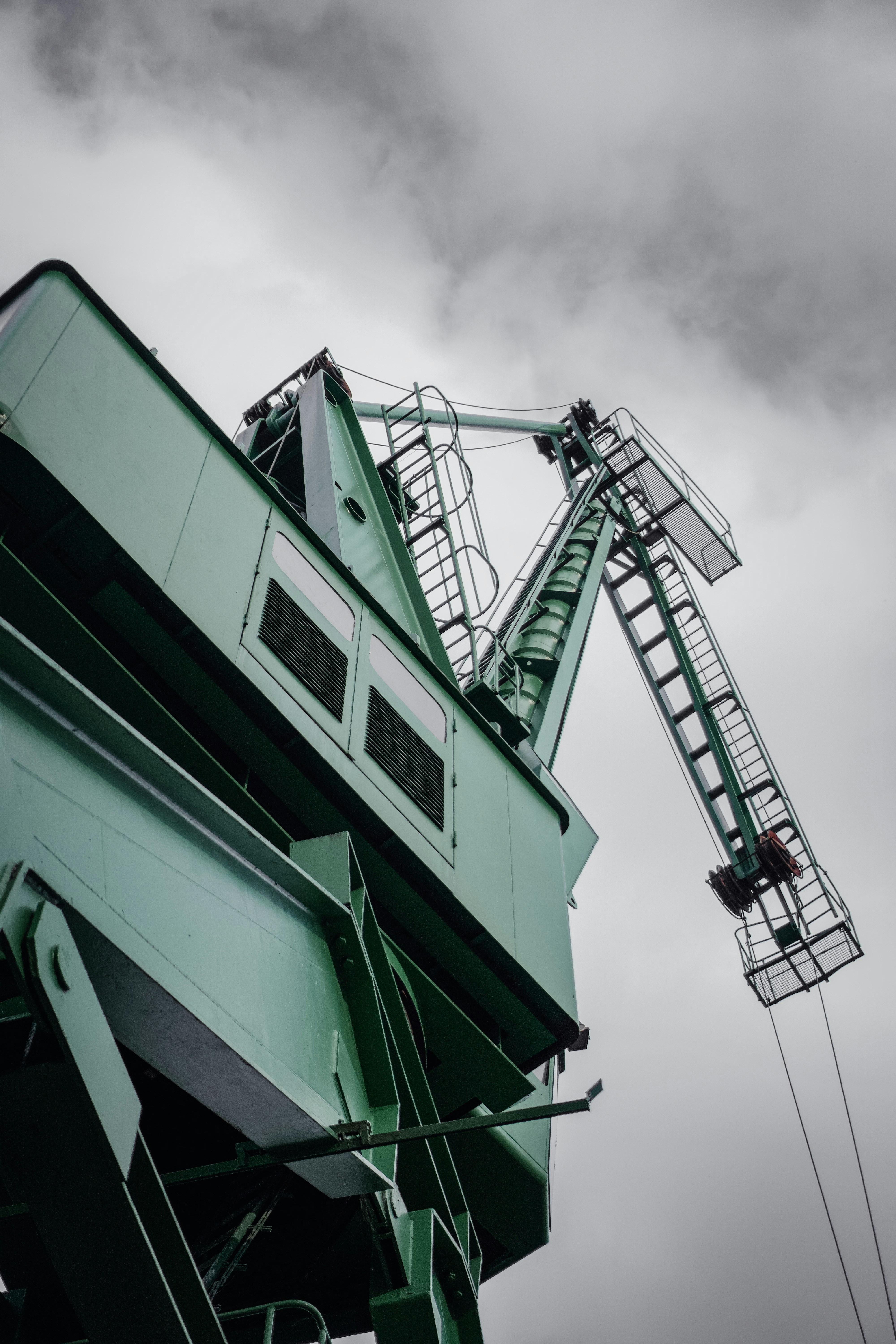 Green Colossus Overcast: a tilted crane slicing through the cloudy sky