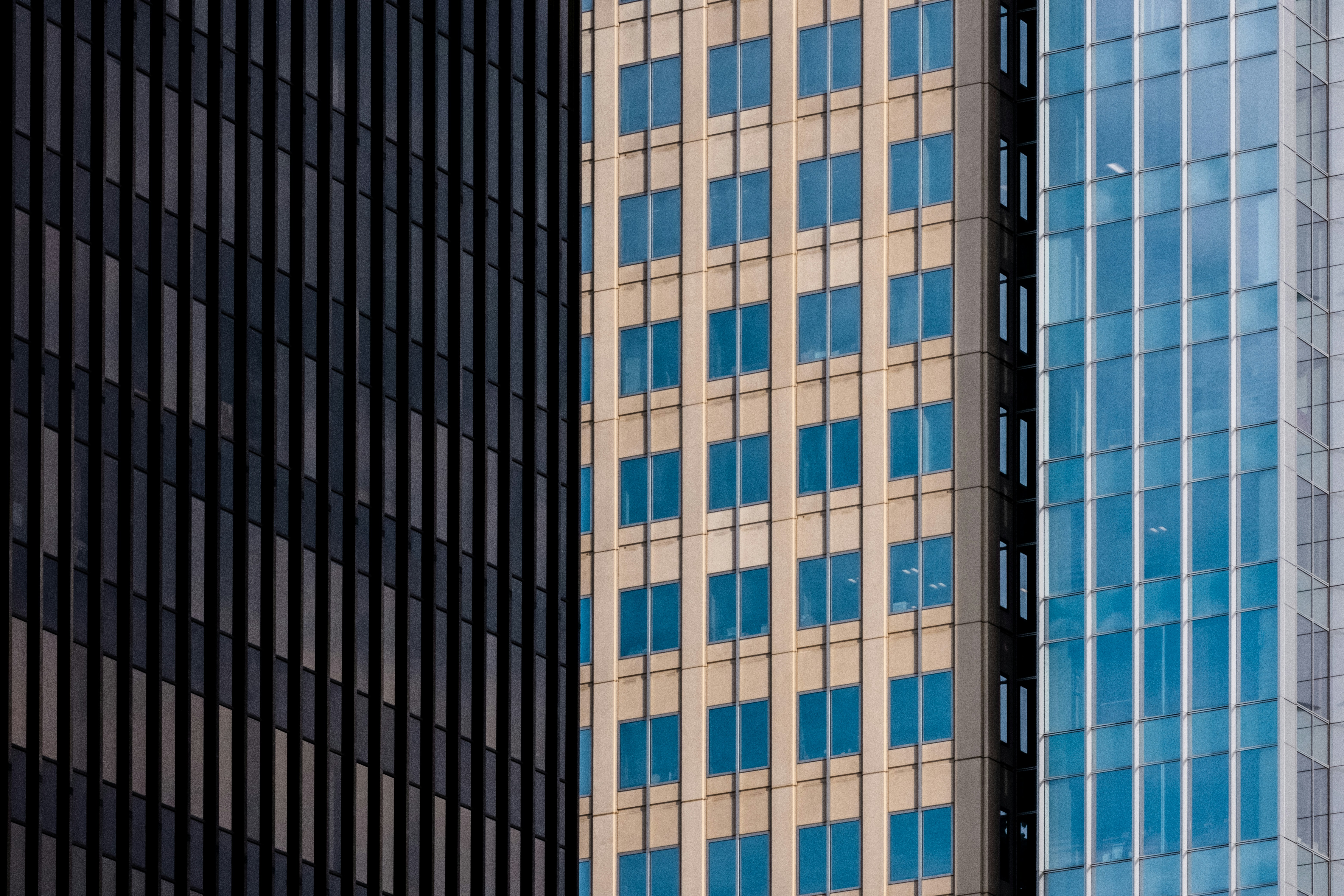 Abstract view of modern skyscrapers showcasing contrasting textures and colors of glass and steel. The interplay of light enhances architectural details.