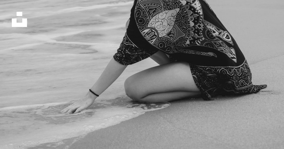 Woman In Black And White Floral Dress Sitting On Concrete Pavement