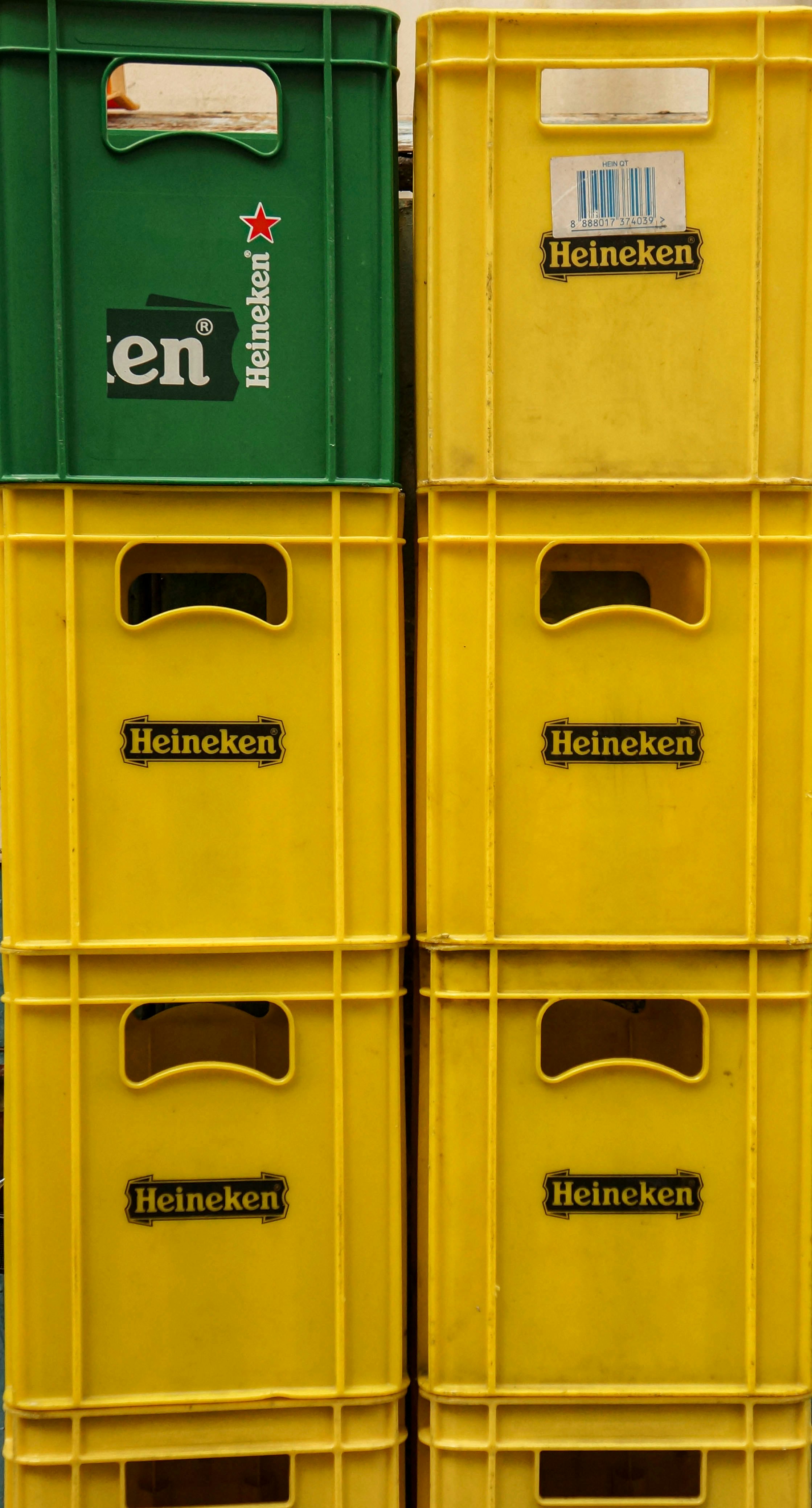 Vertical arrangement of yellow and green crates, prominently featuring Heineken branding. The crates are stacked in a neat formation, showcasing their vibrant colors.