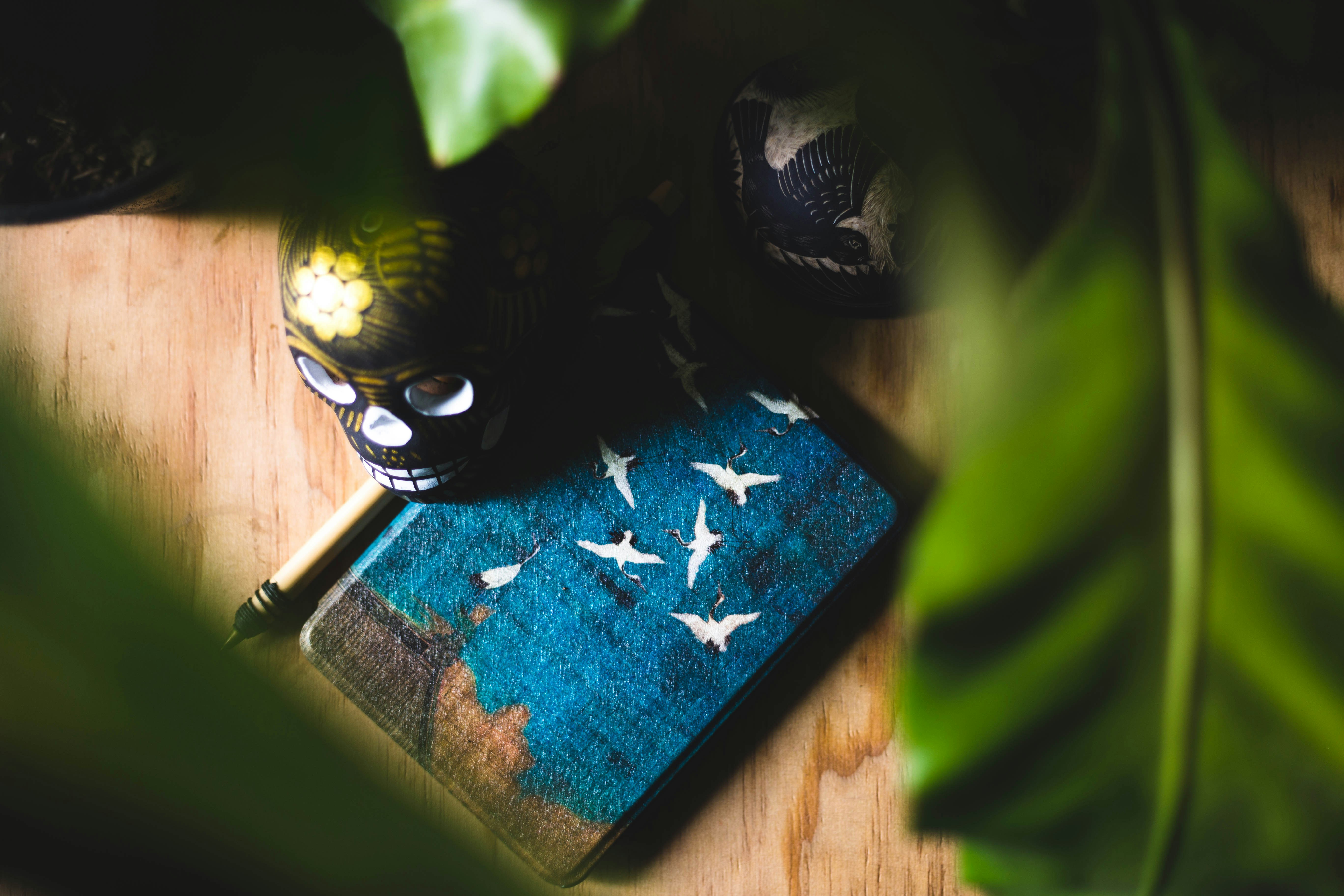 Birds over a painted card: quiet still life in a leafy frame