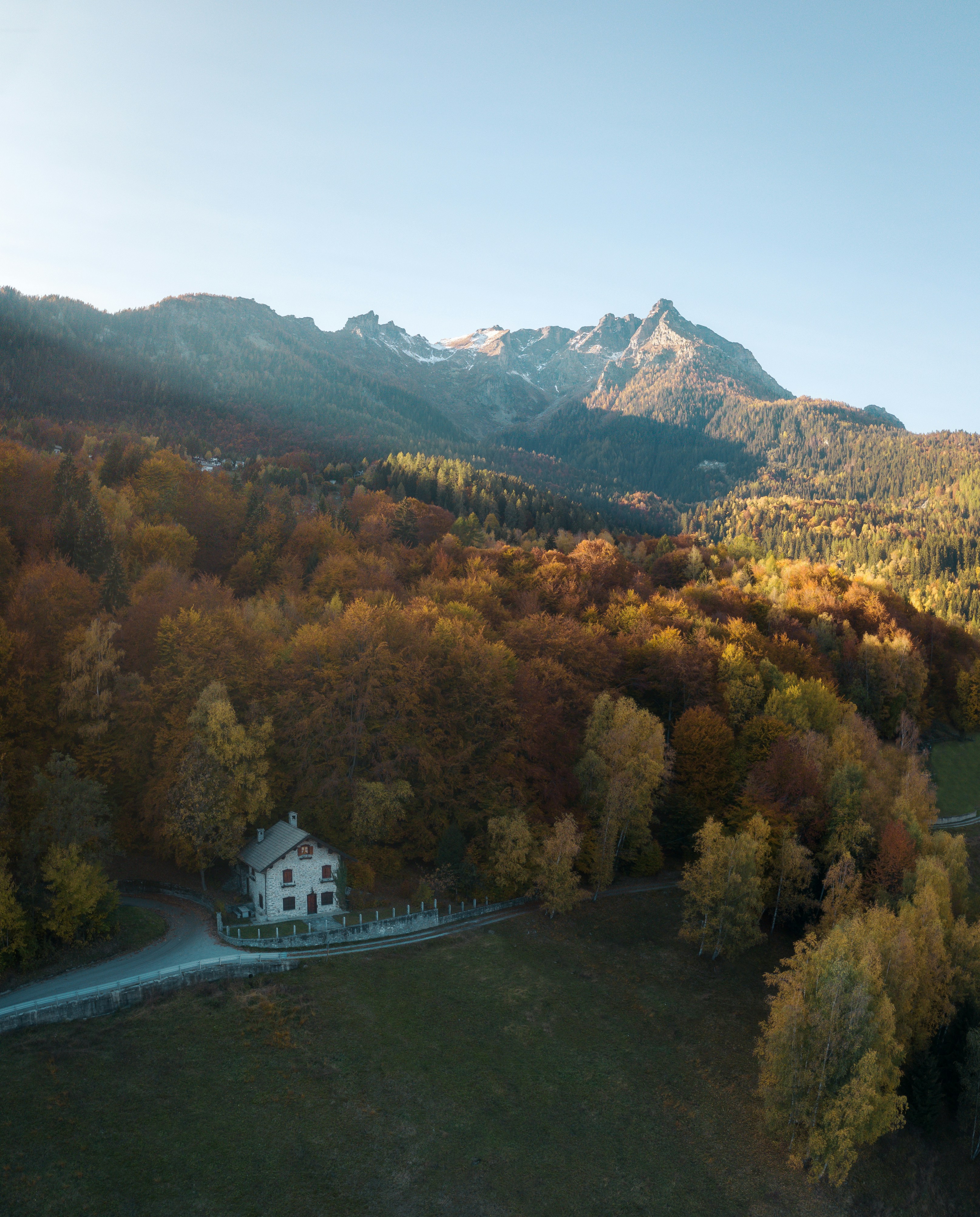 Charming house surrounded by vibrant autumn foliage and majestic mountains in the background.