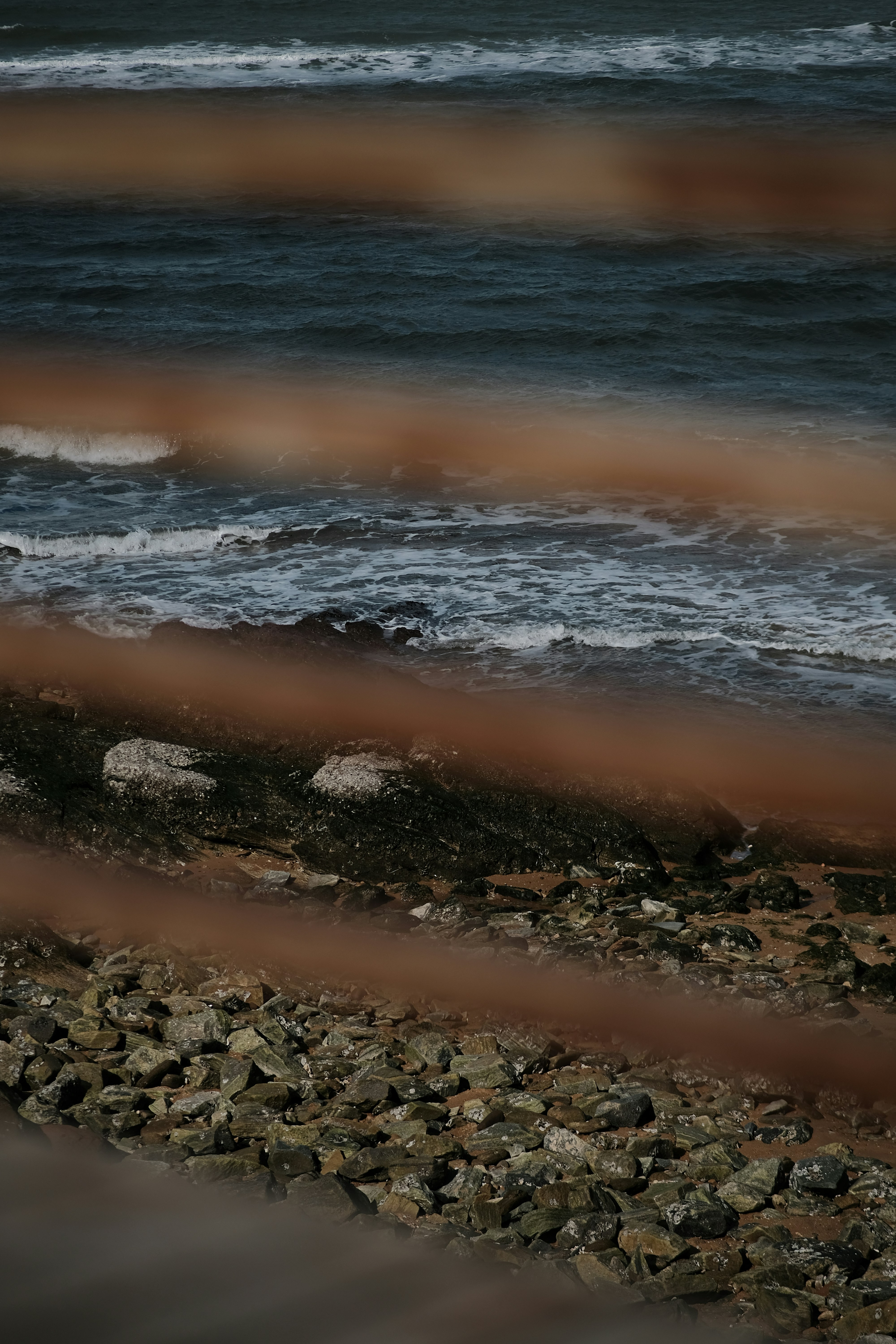 brown and black stones near body of water during daytime