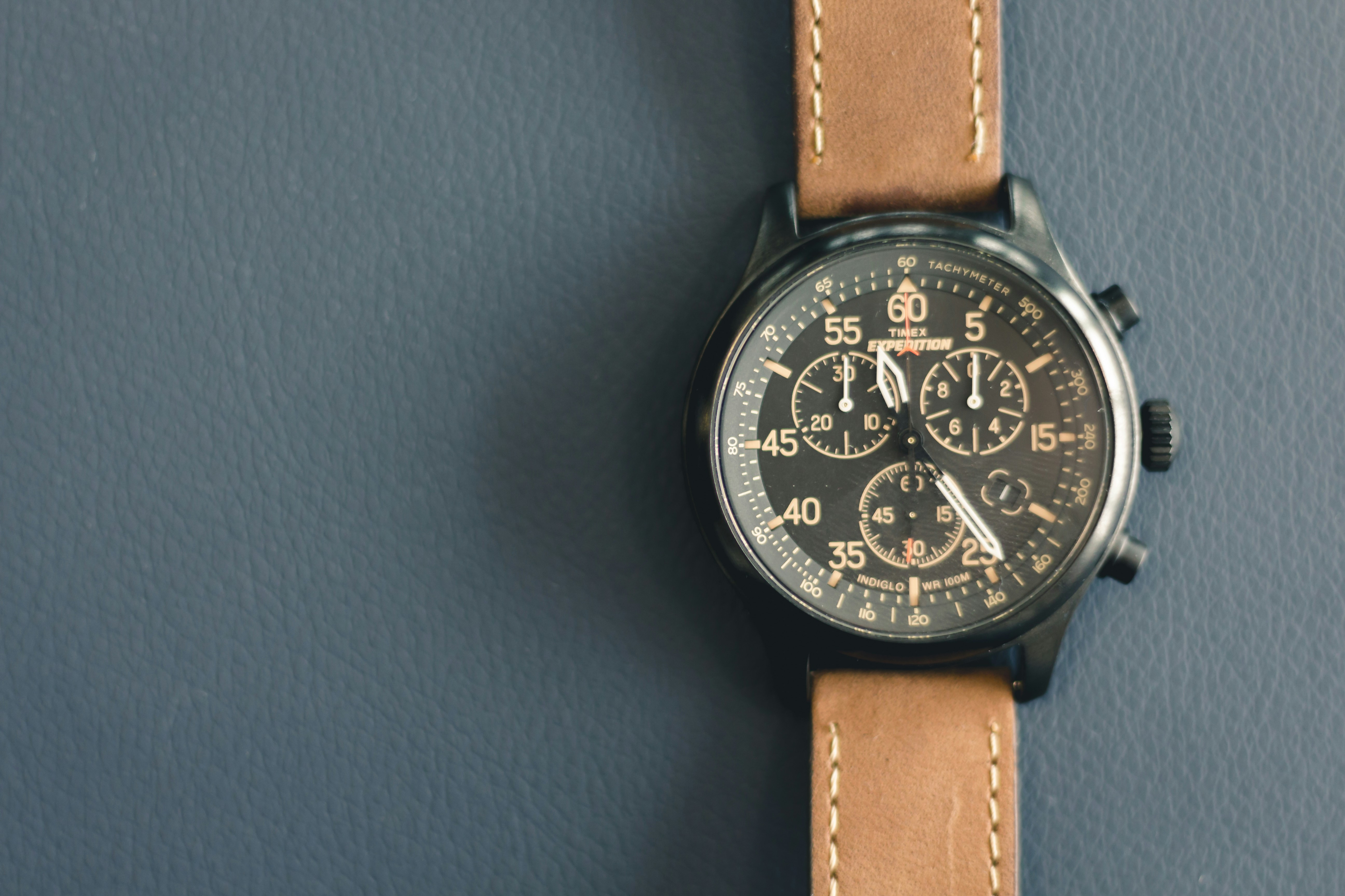 Chronograph watch with a black face and brown leather strap, highlighting intricate details and craftsmanship.