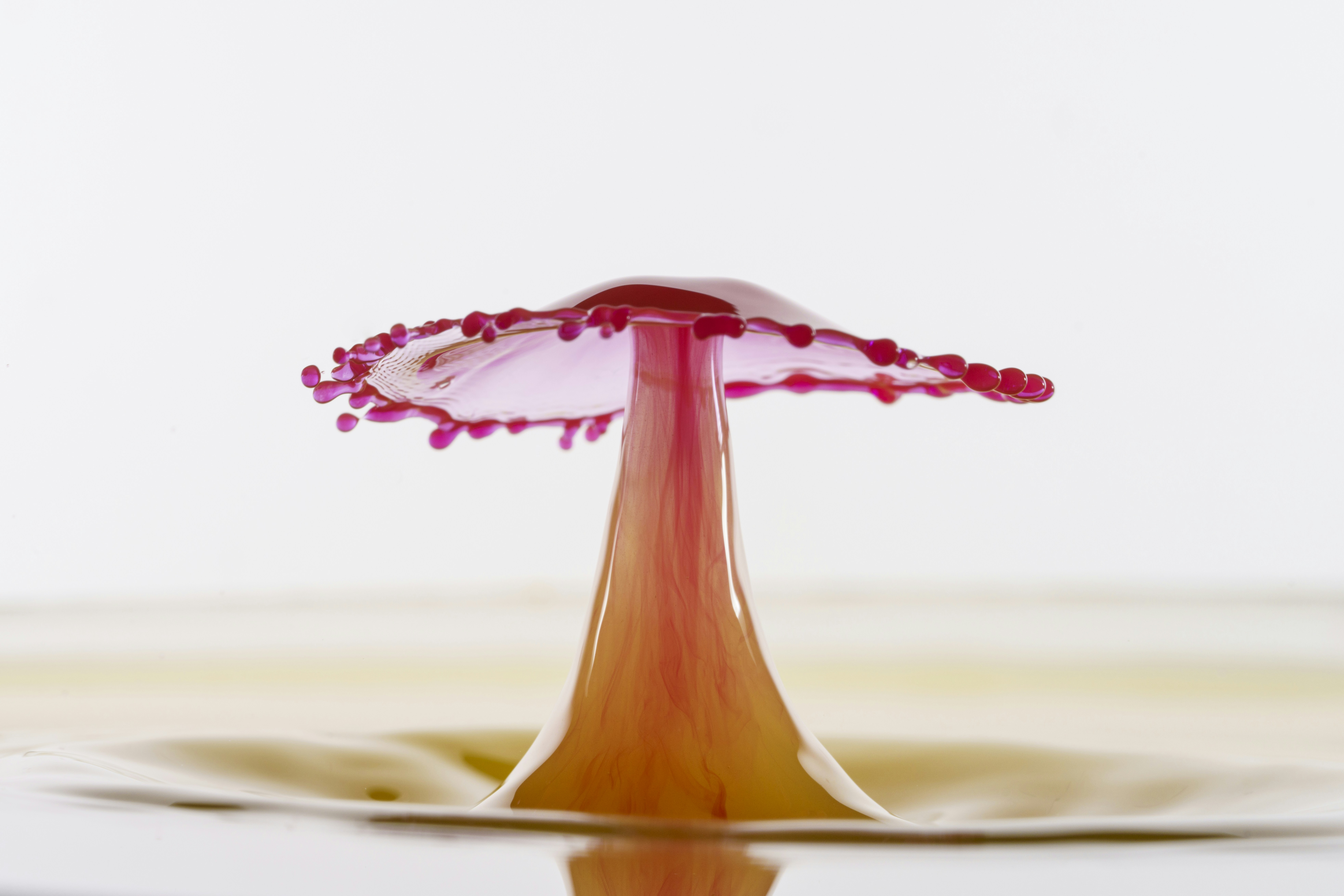 Liquid Mushroom Crown: A Red-Tinted Plume Rising from a Quiet Surface