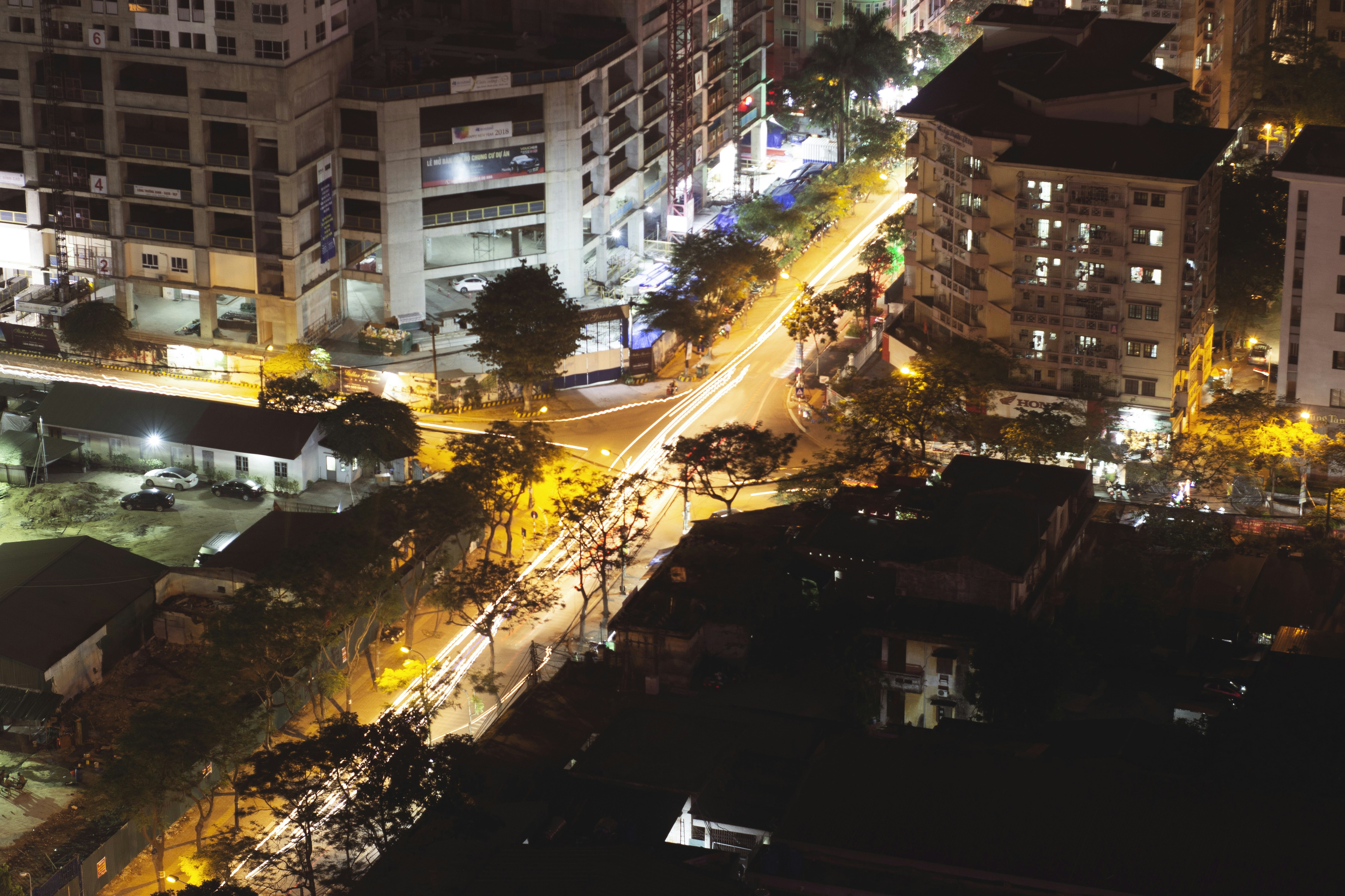 Nighttime cityscape showcasing illuminated streets and buildings with moving vehicle trails. The scene captures the dynamic energy of urban life.