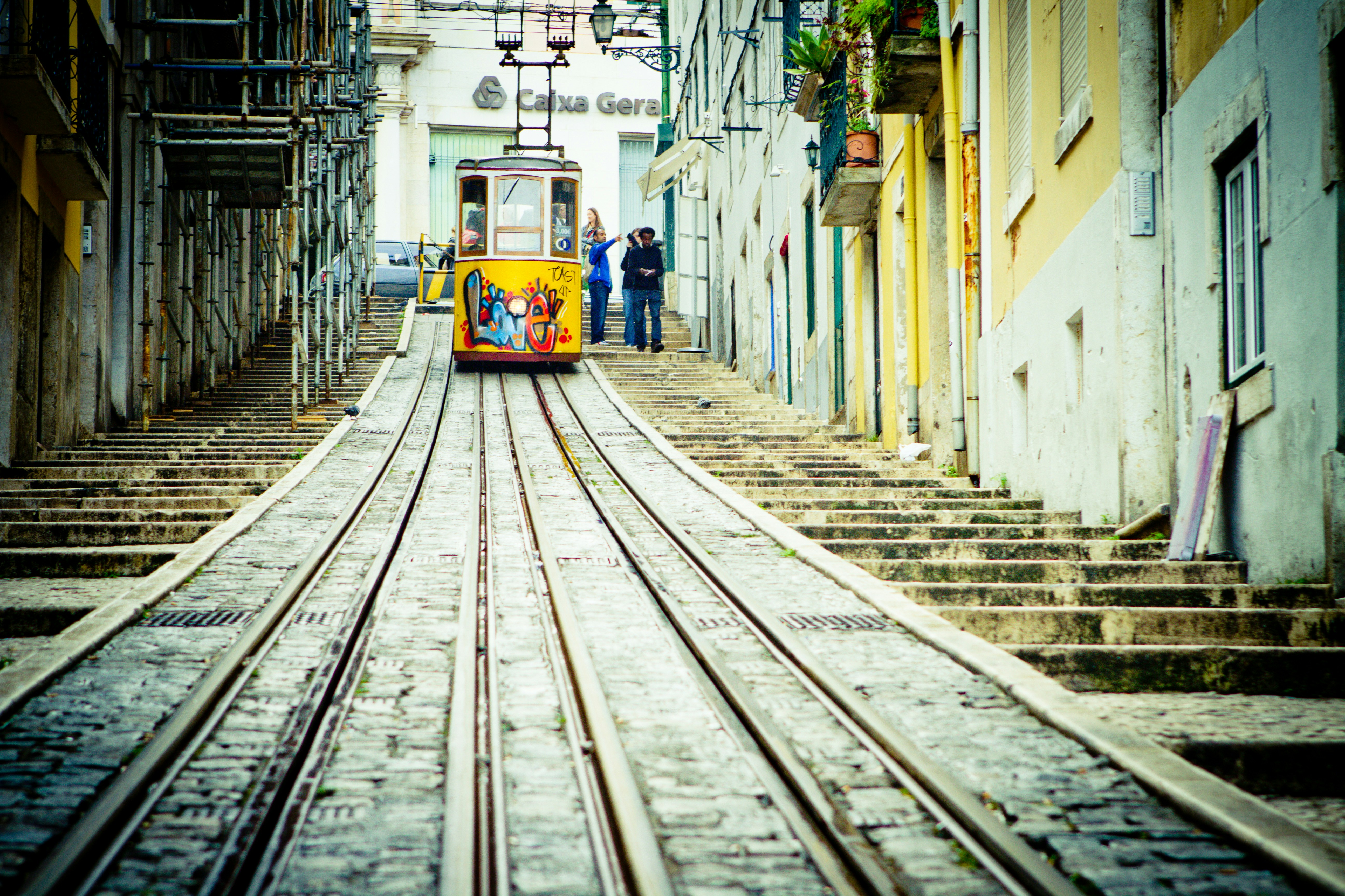Yellow and white train in between of white concrete buildings during ...