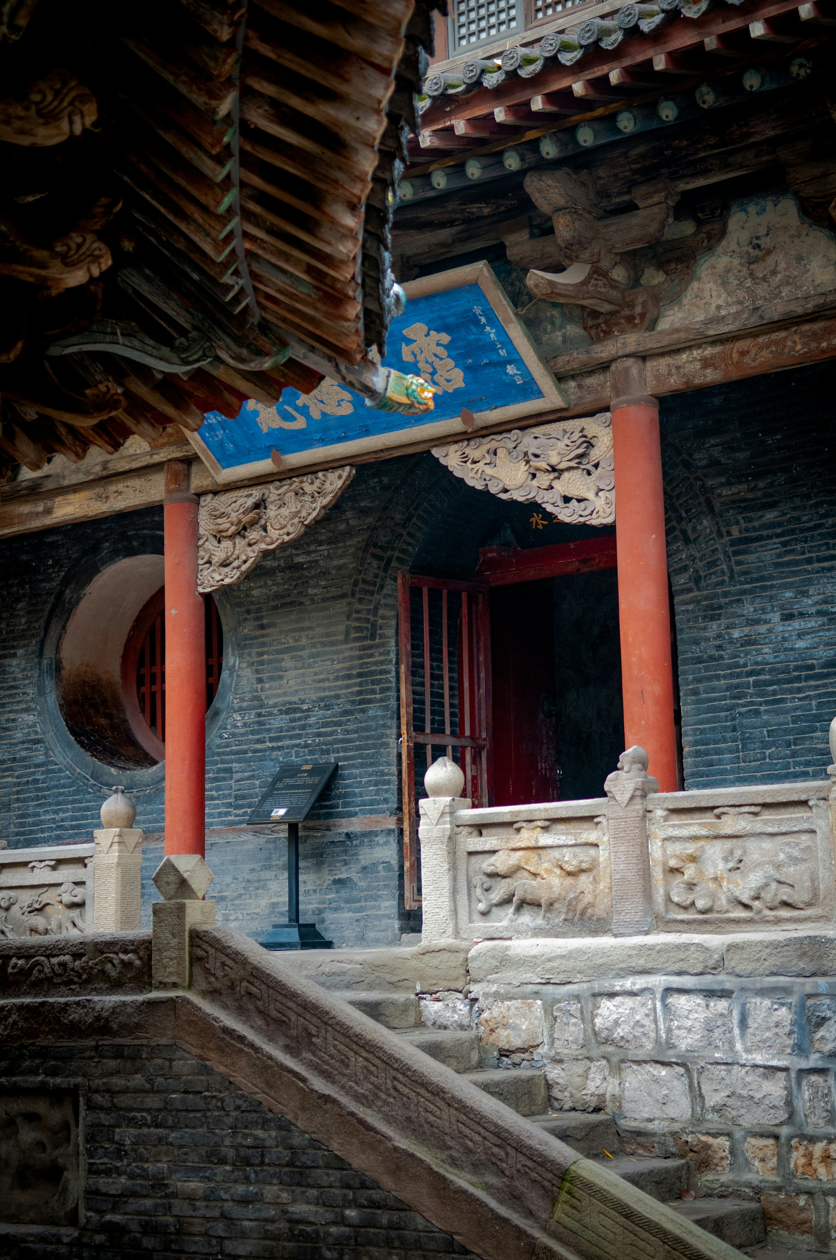 Ornately carved stone railing and vibrant wooden beams of a traditional temple.