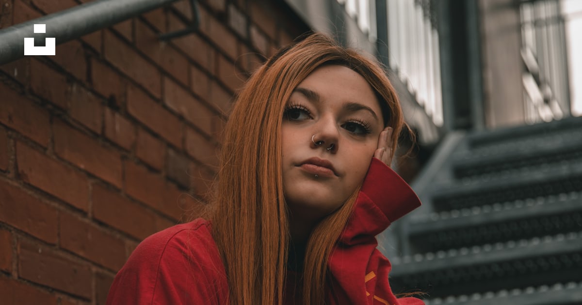 赤いパーカーと青いデニムジーンズを着た女性が階段に座っているの写真 Unsplashの人間の無料画像