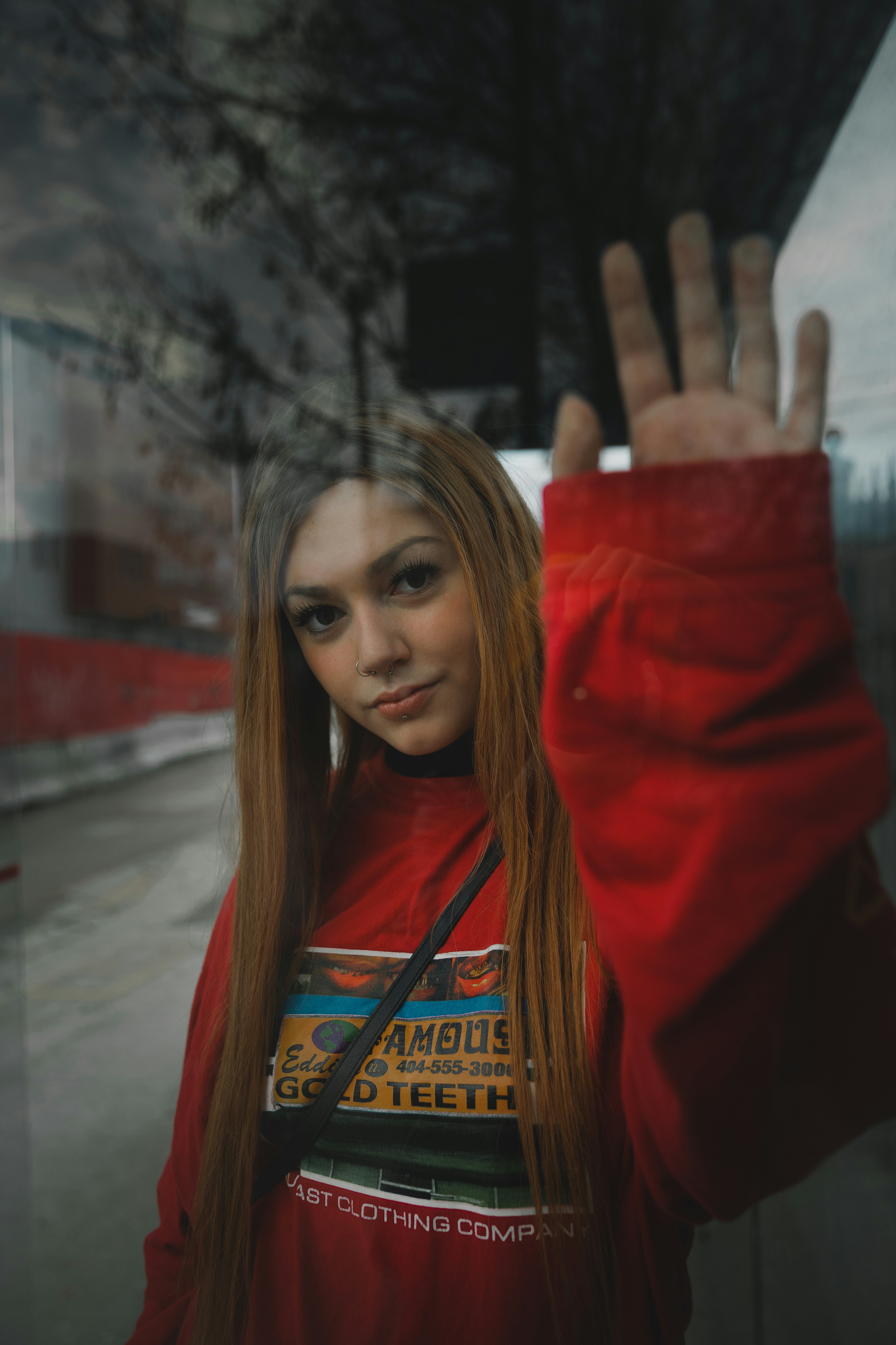 Through the Glass: Red Hoodie Portrait with a Reaching Hand