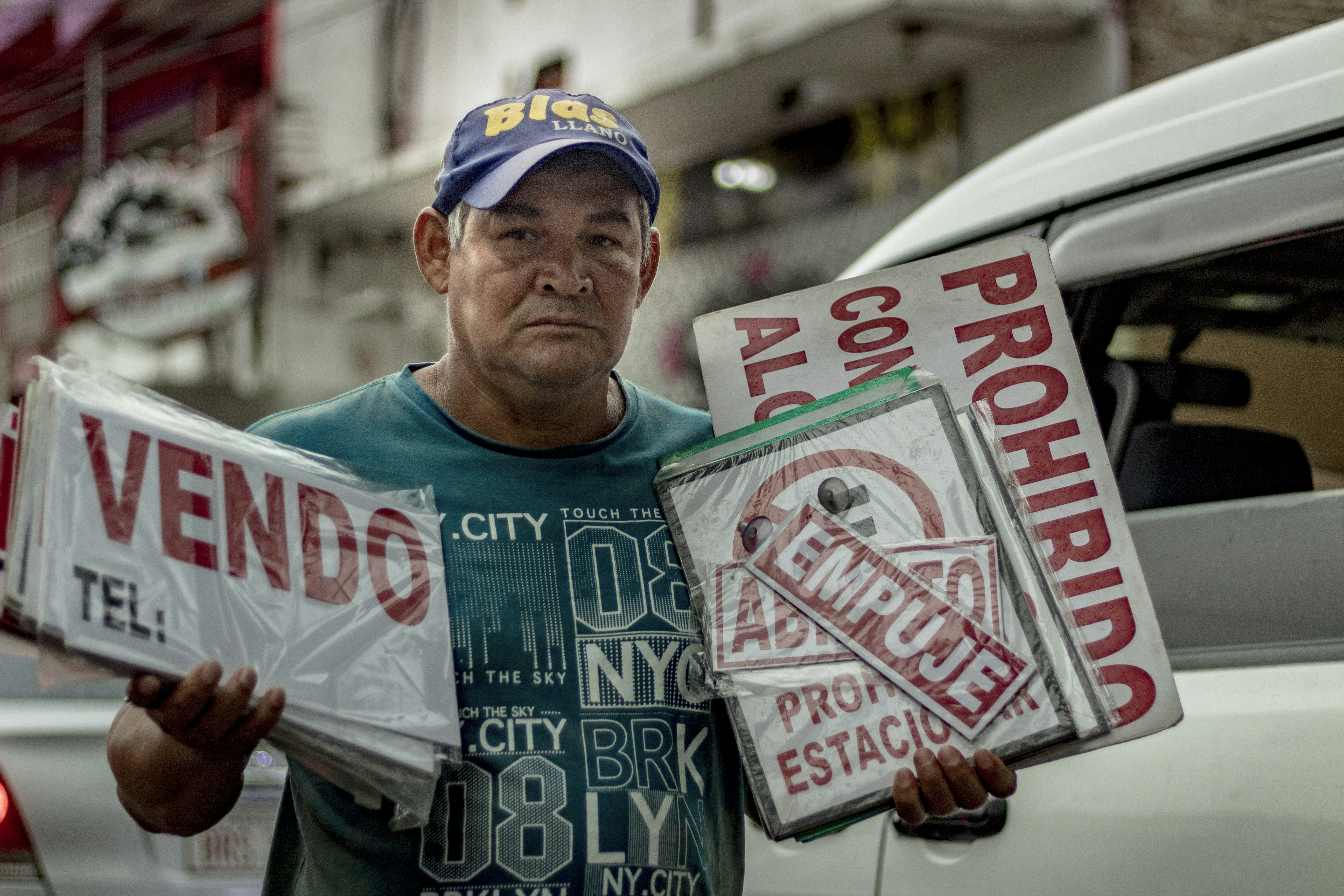 A man holding two signs in front of a car photo – Free Street Image on ...