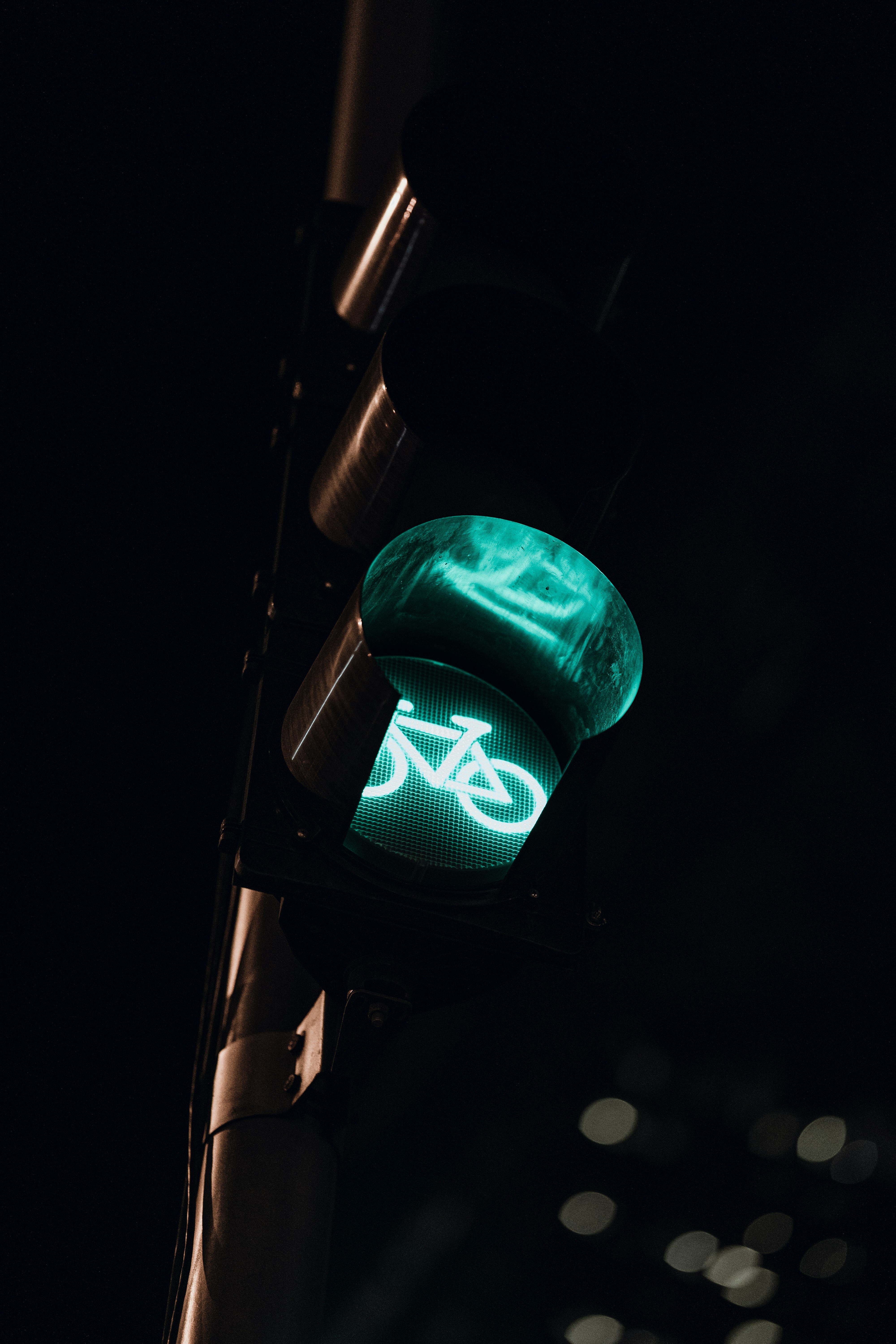 Green bicycle signal illuminated against a dark urban backdrop, highlighting the importance of cycling infrastructure.