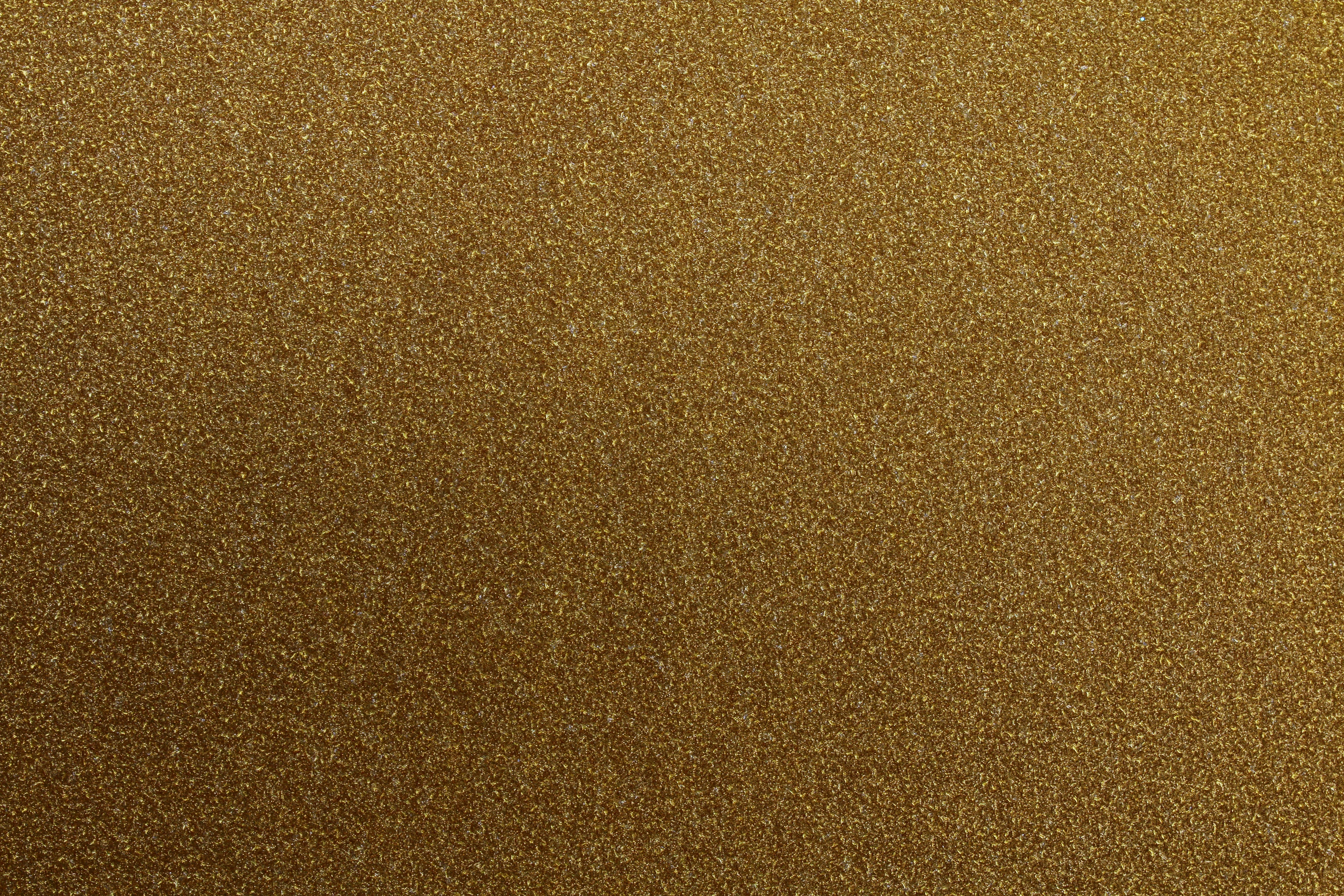 Textured surface with a golden hue, resembling fine sand or a metallic finish. Ideal for backgrounds or design elements.