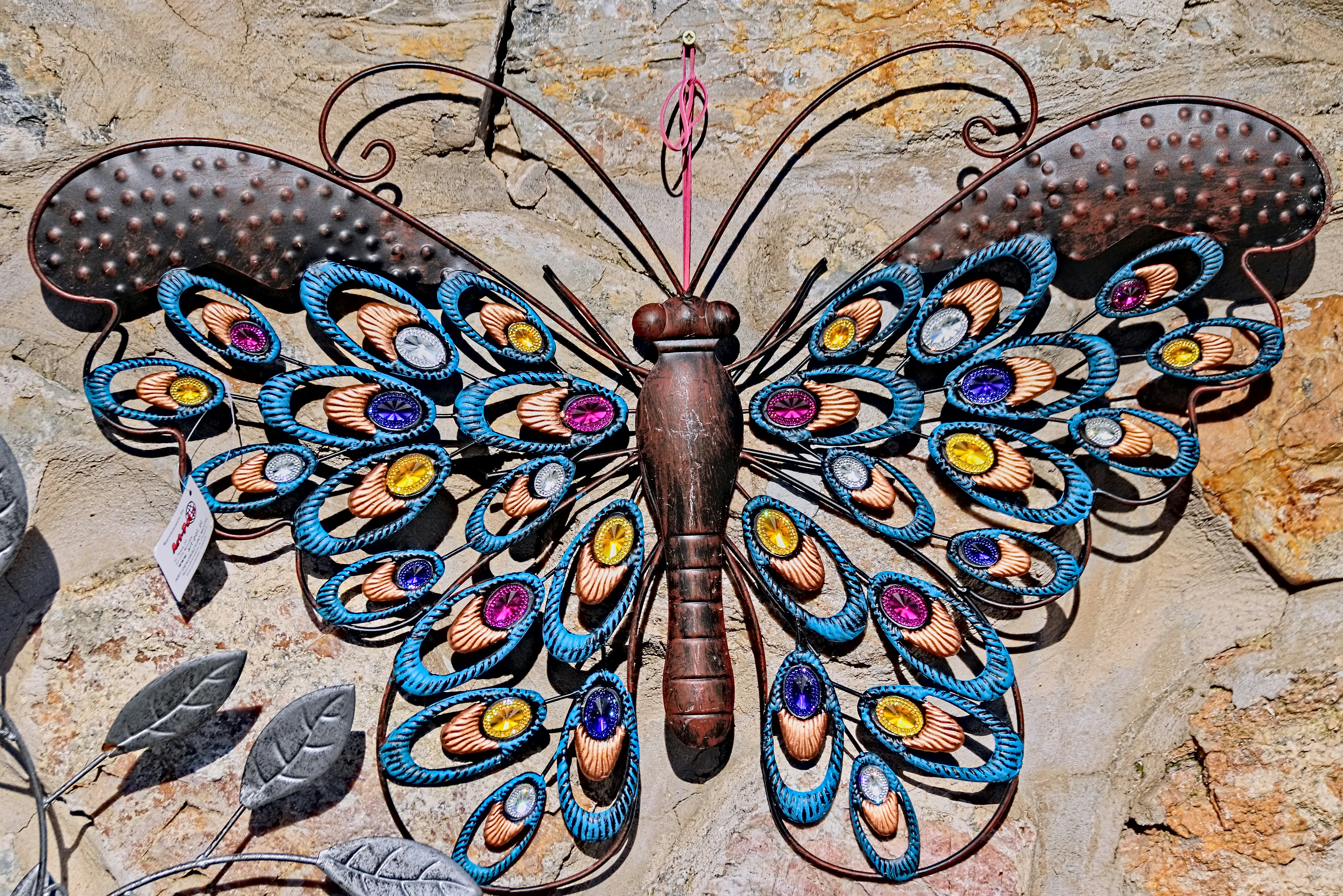Wired Wings: A Vibrant Metal Butterfly Adorning a Rustic Stone Wall