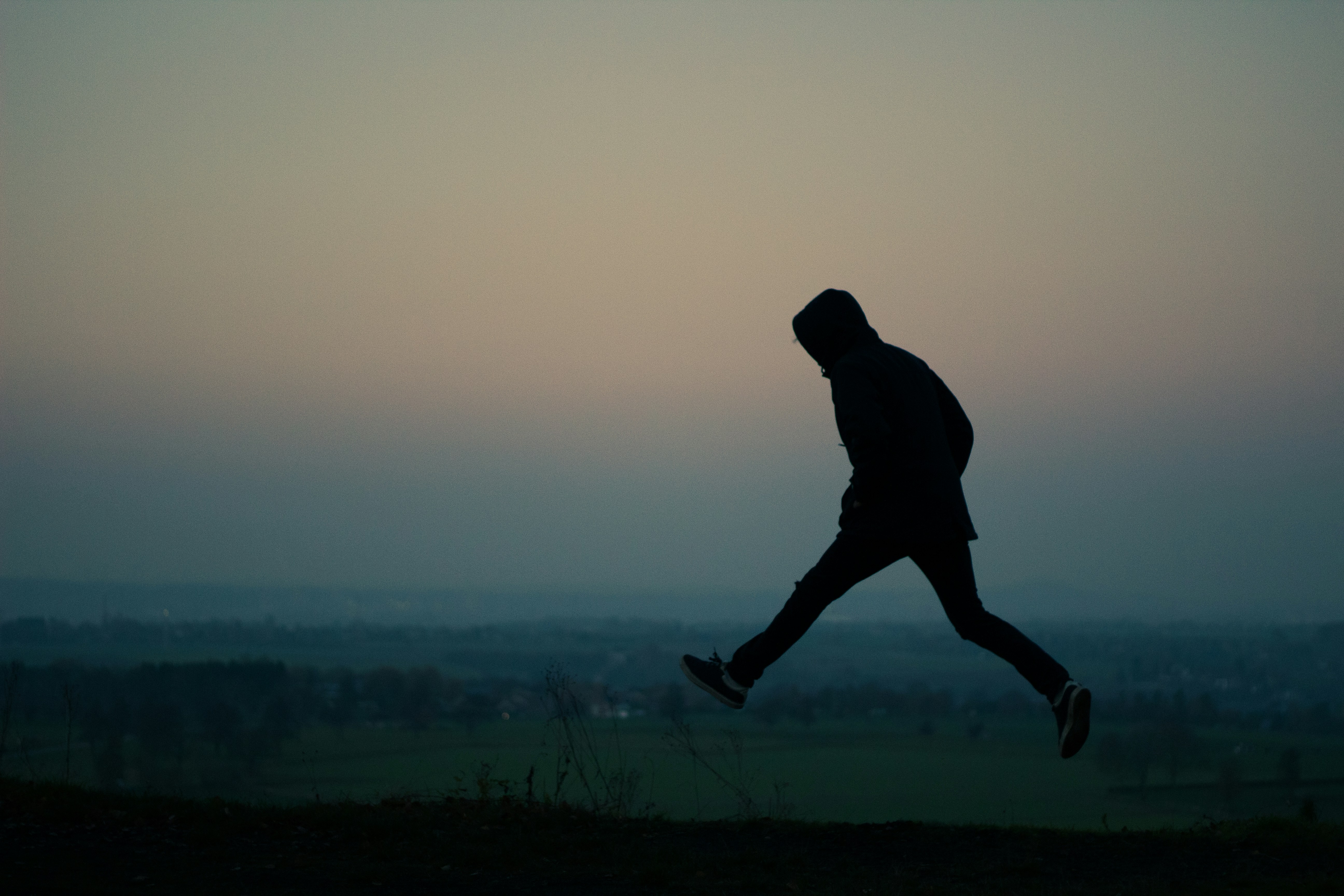 Silhouette of a person leaping against a soft gradient sky at dusk, capturing a moment of freedom and movement.