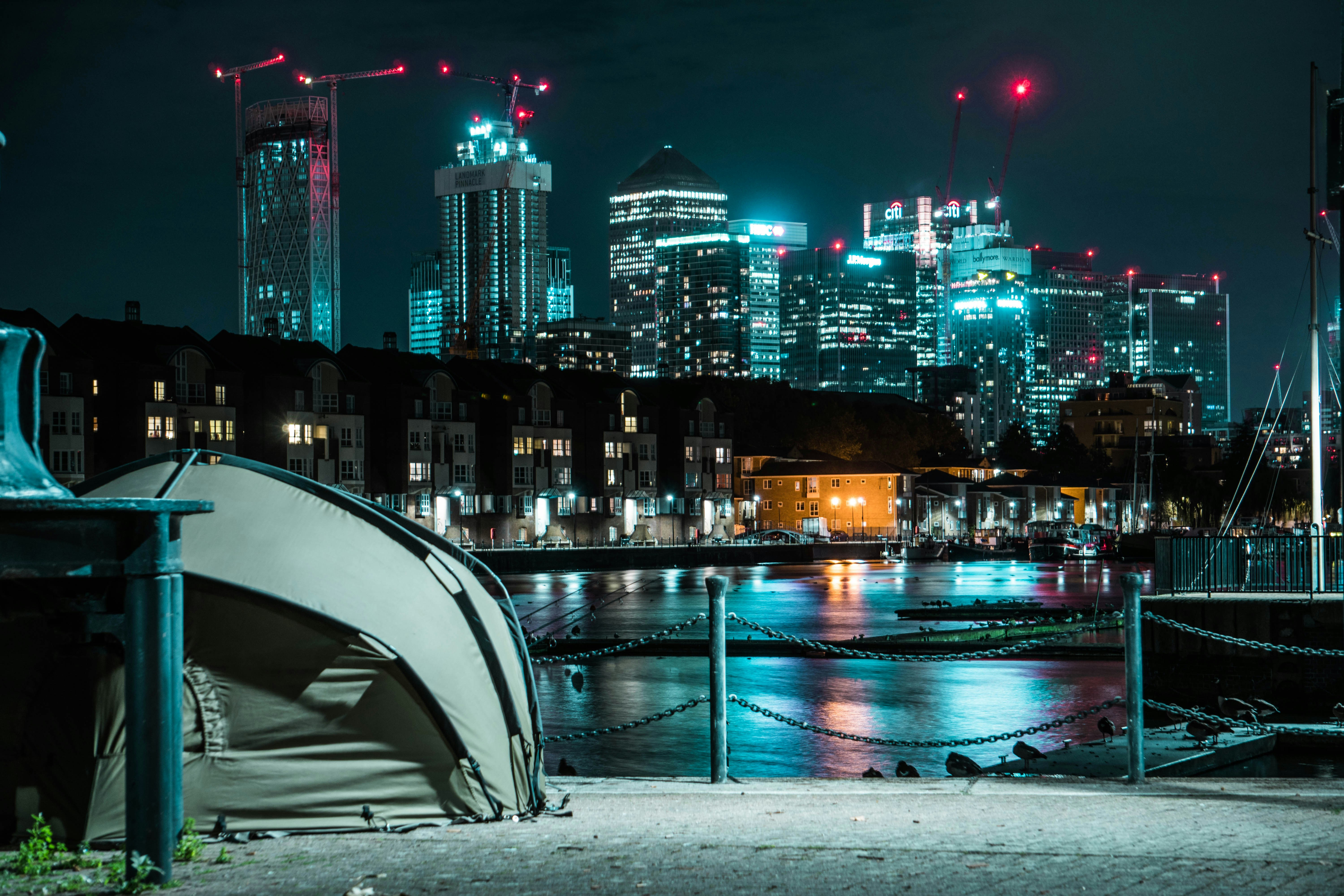 Harbor Neon: A Tent Framed by Neon Skyline Reflections