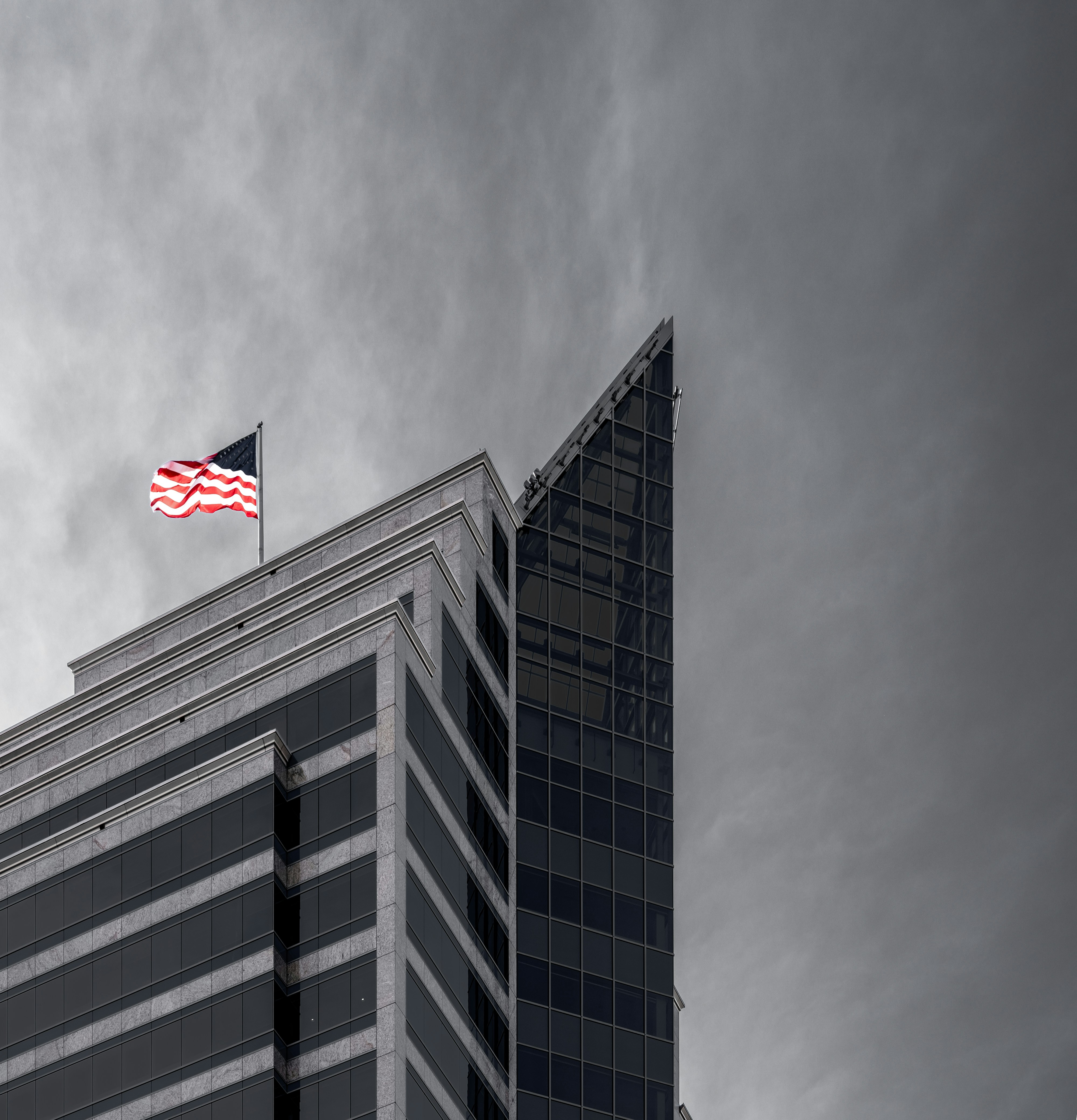 Flag atop a sharp-edged tower slicing into a stormy sky