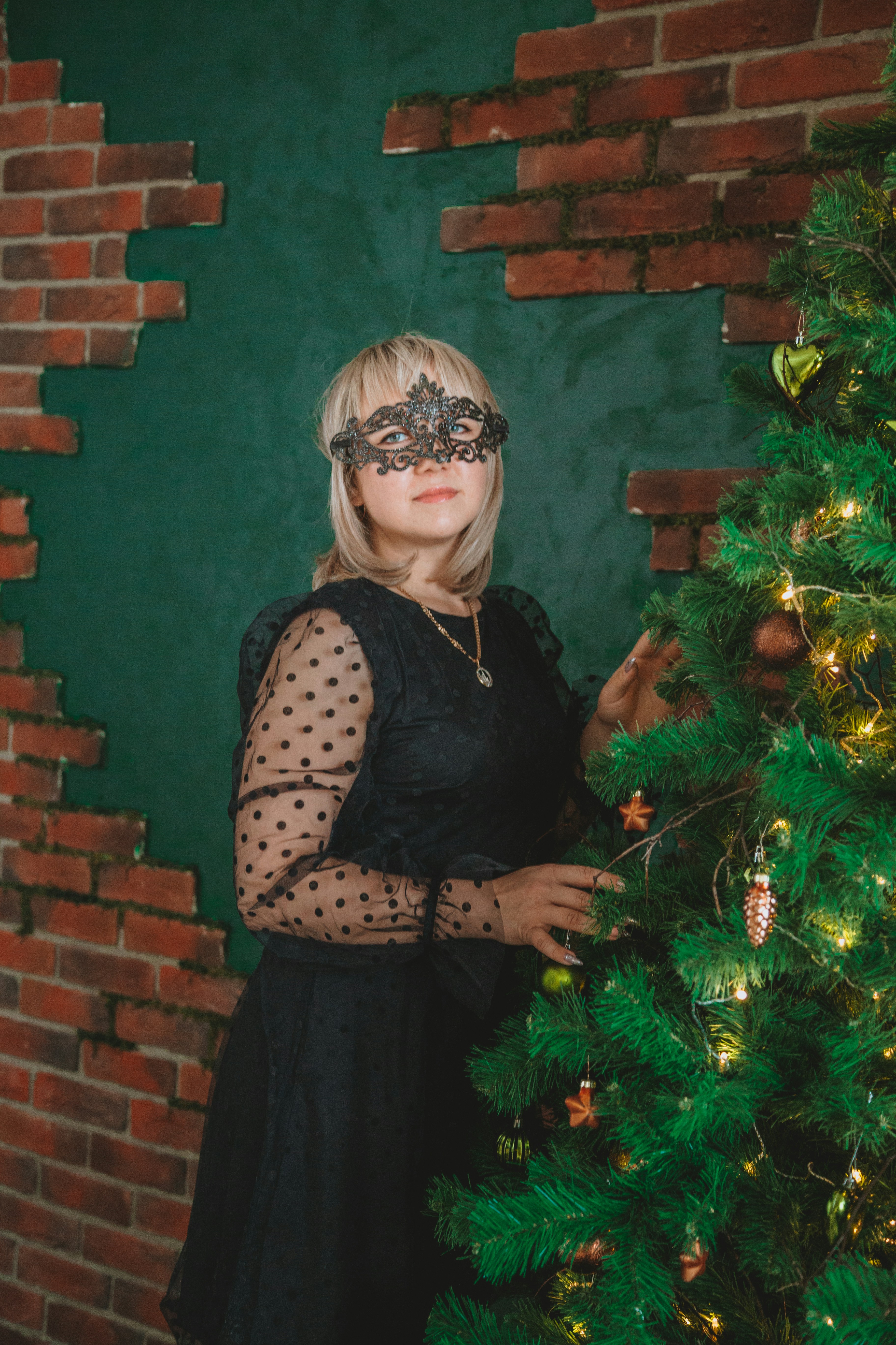 woman in black and white polka dot sleeveless dress standing beside green christmas tree