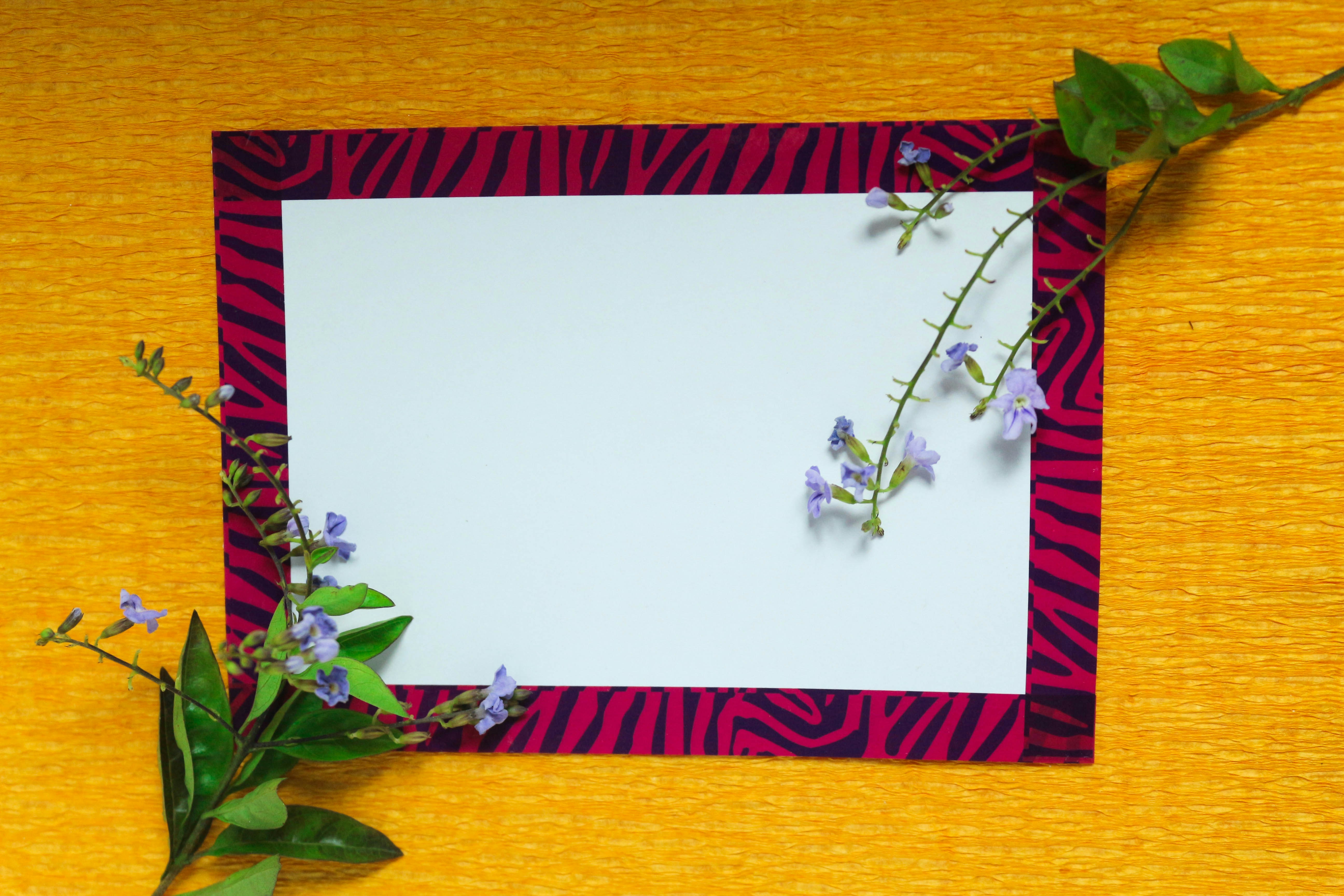Purple sprigs frame a white card within a striped magenta border on a golden surface