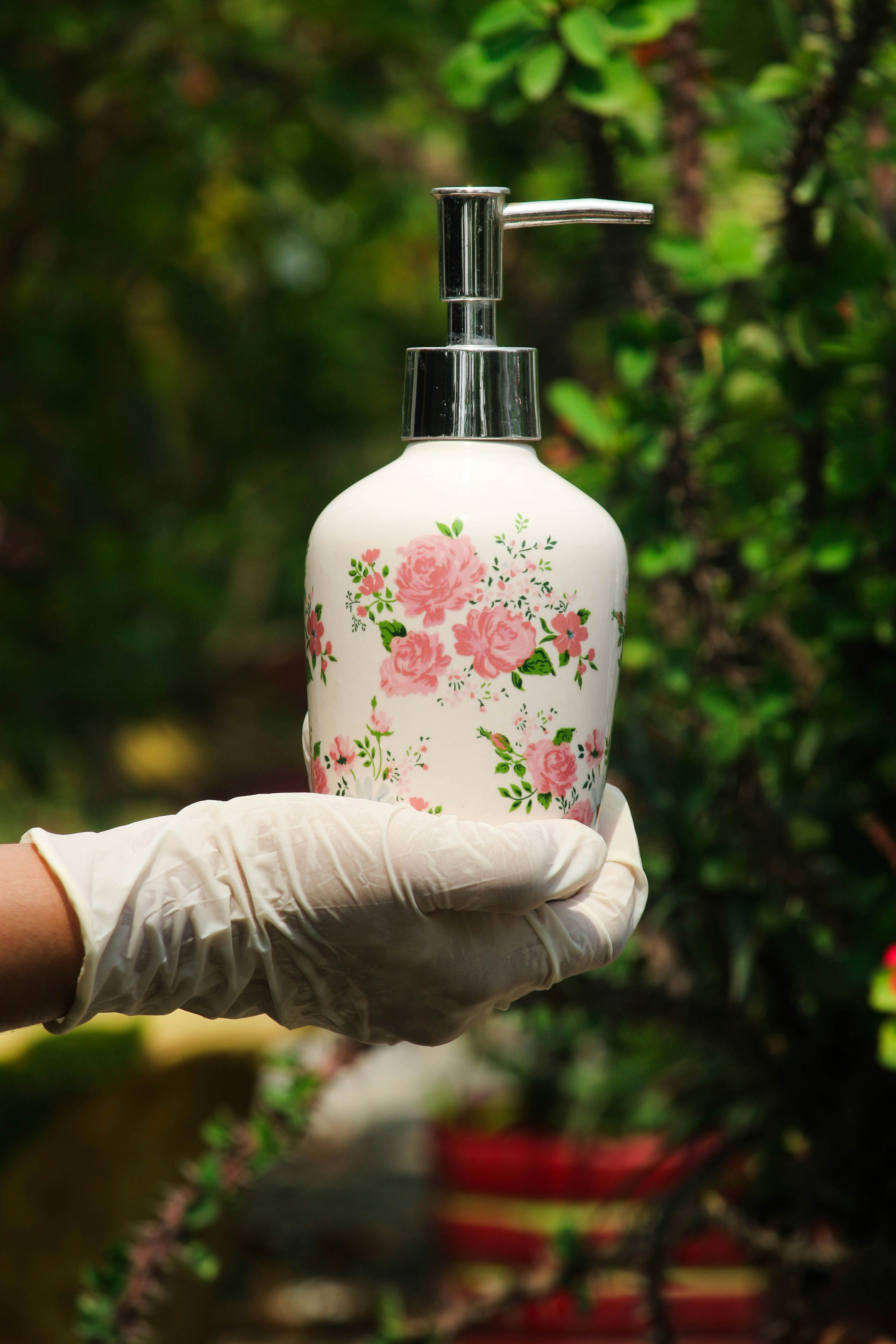 person holding white and pink floral pump bottle