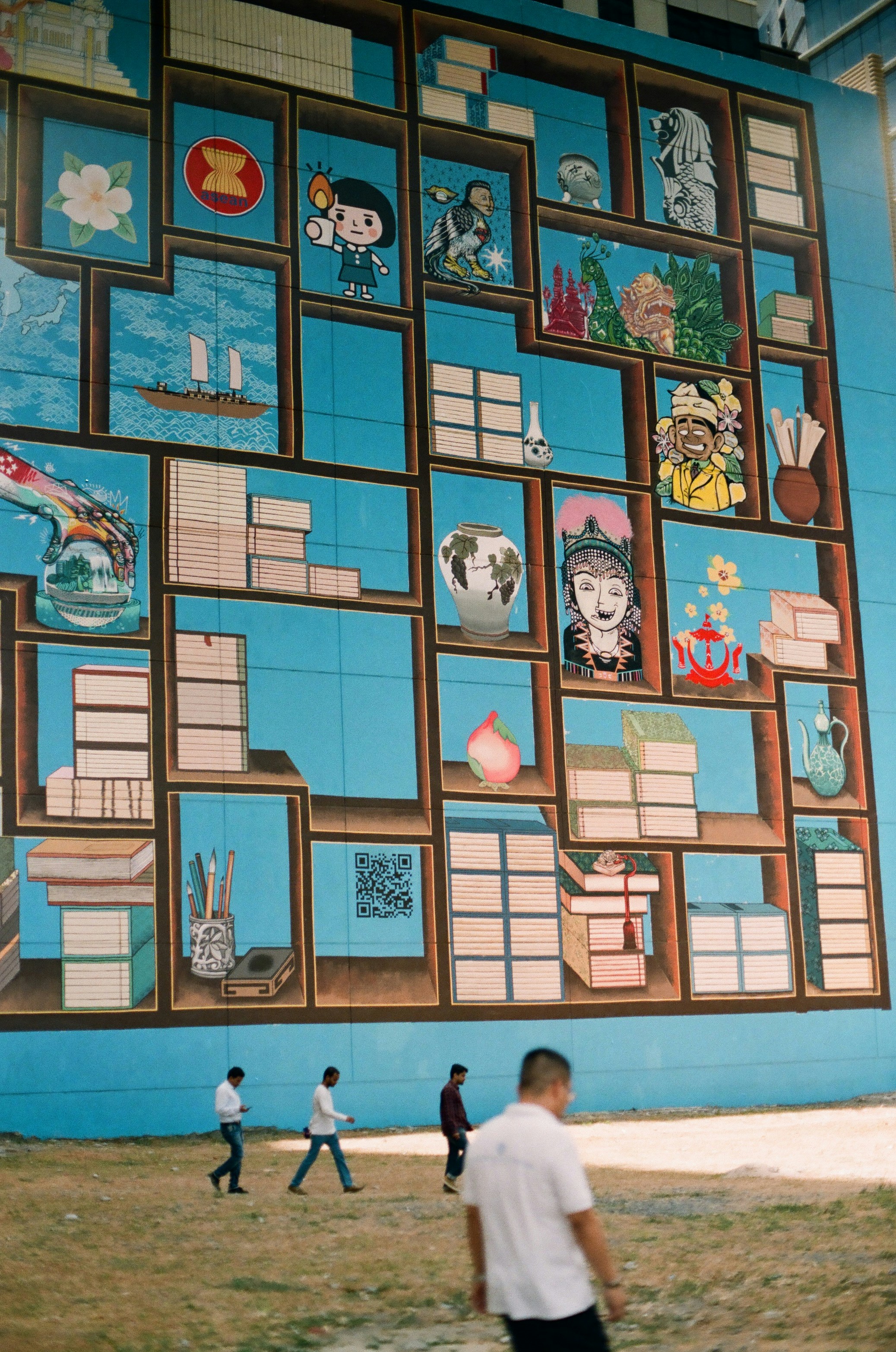 A man walking past a blue building with many pictures on it photo ...