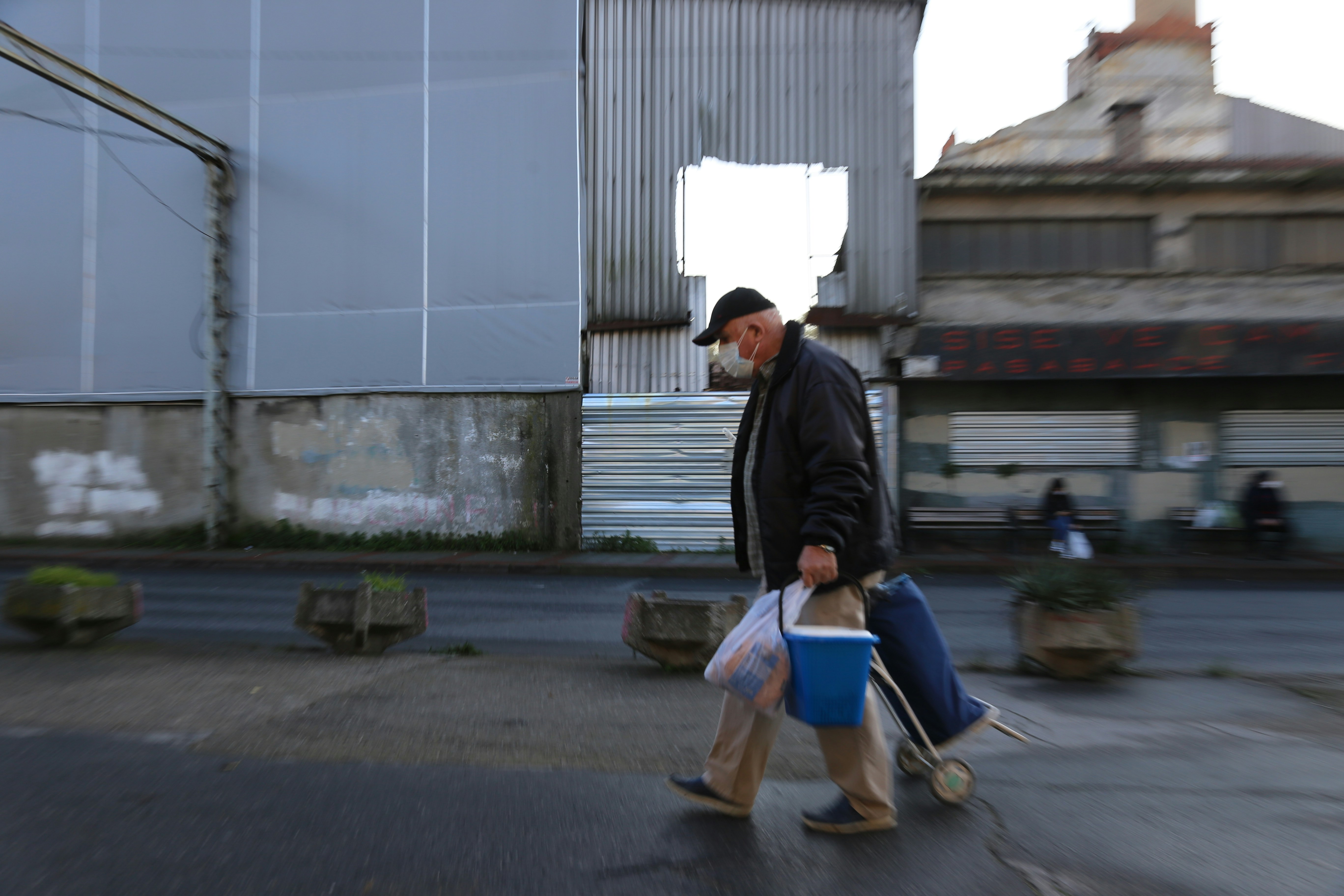 Hard-worn Street Rhythm: A Man Hauls a Cart Through a Weathered Industrial Street