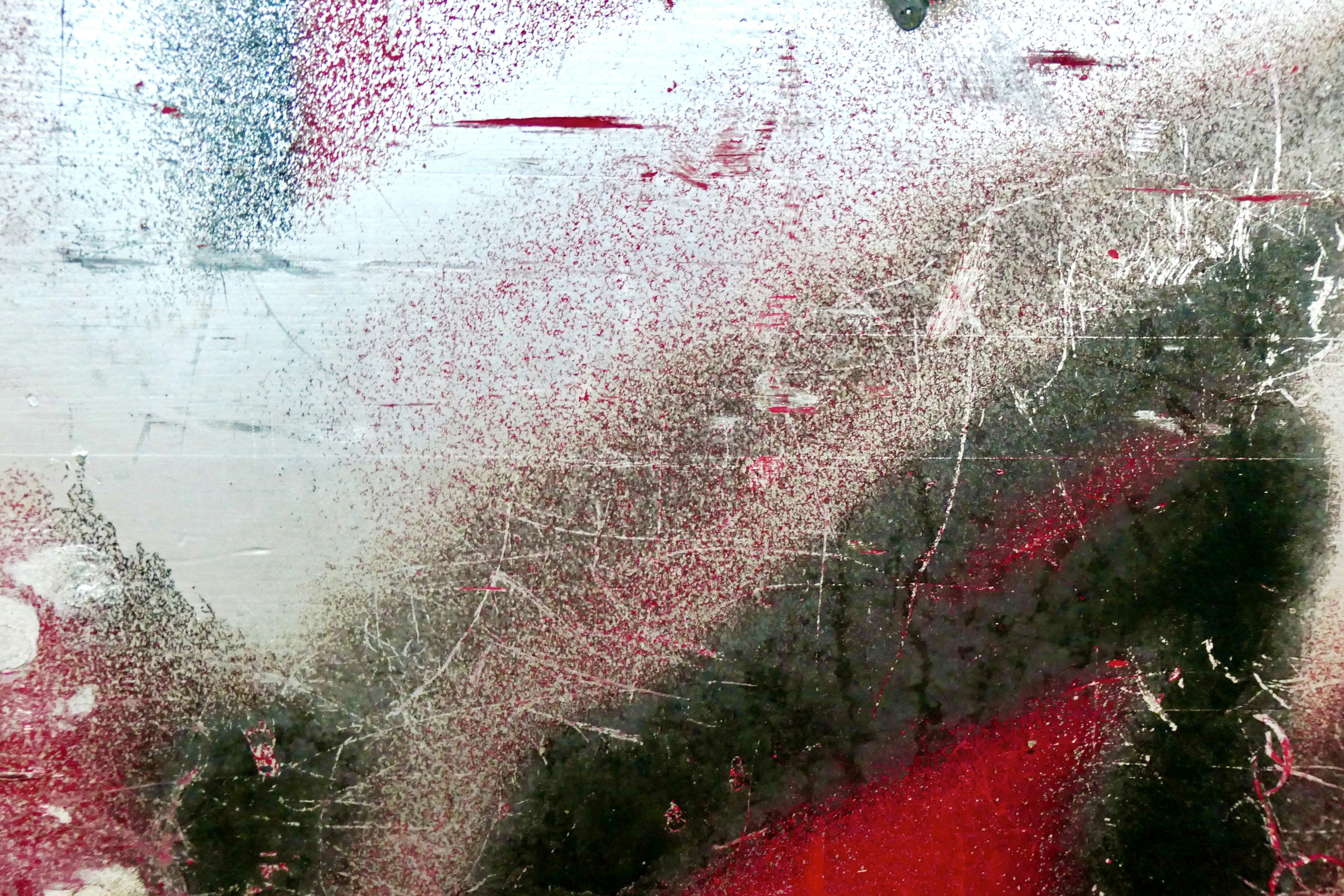 Abstract texture featuring a blend of red, black, and gray paint splatters on a weathered surface.