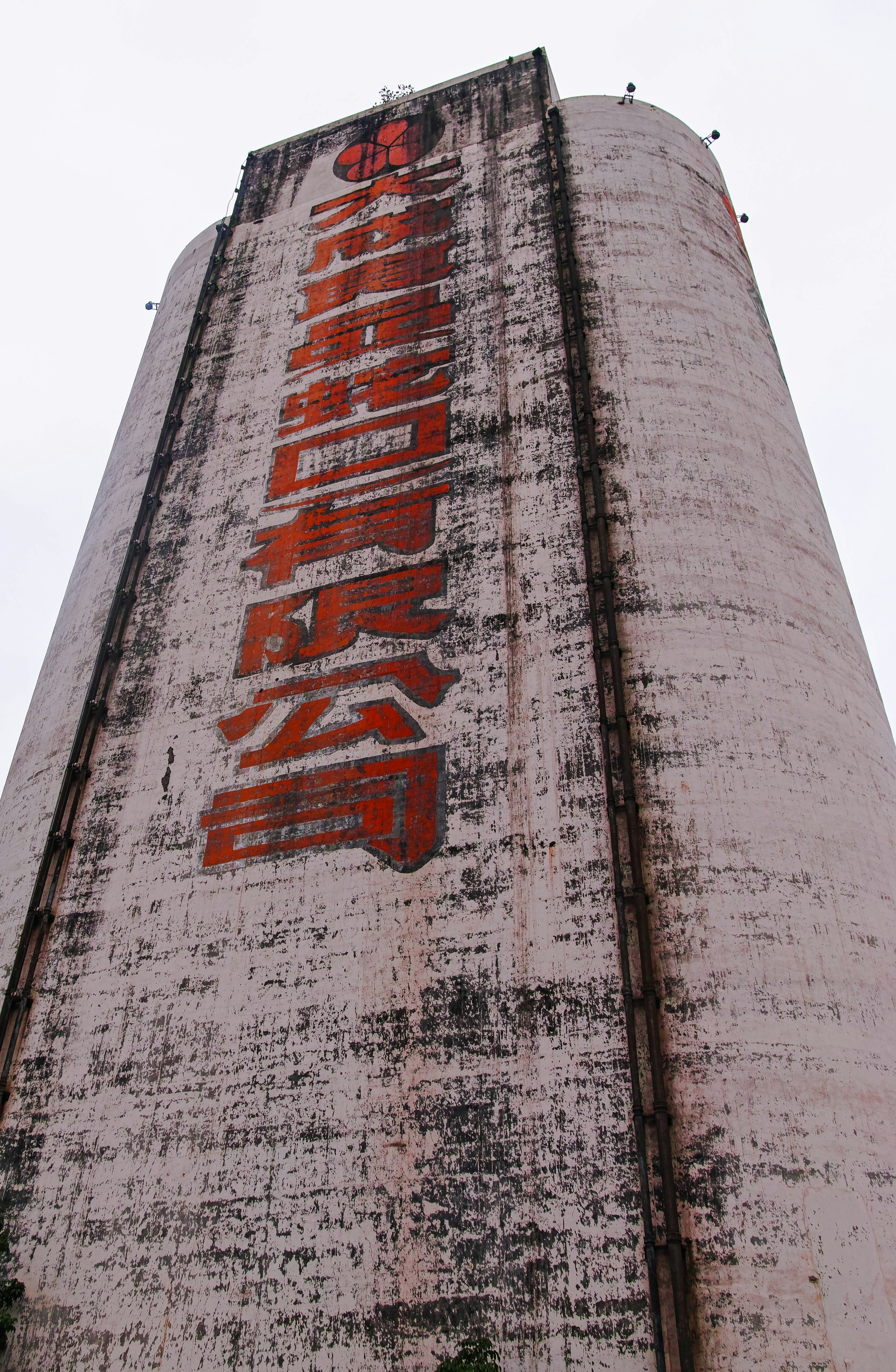 A towering concrete silo adorned with faded red lettering, showcasing the passage of time and industrial history.