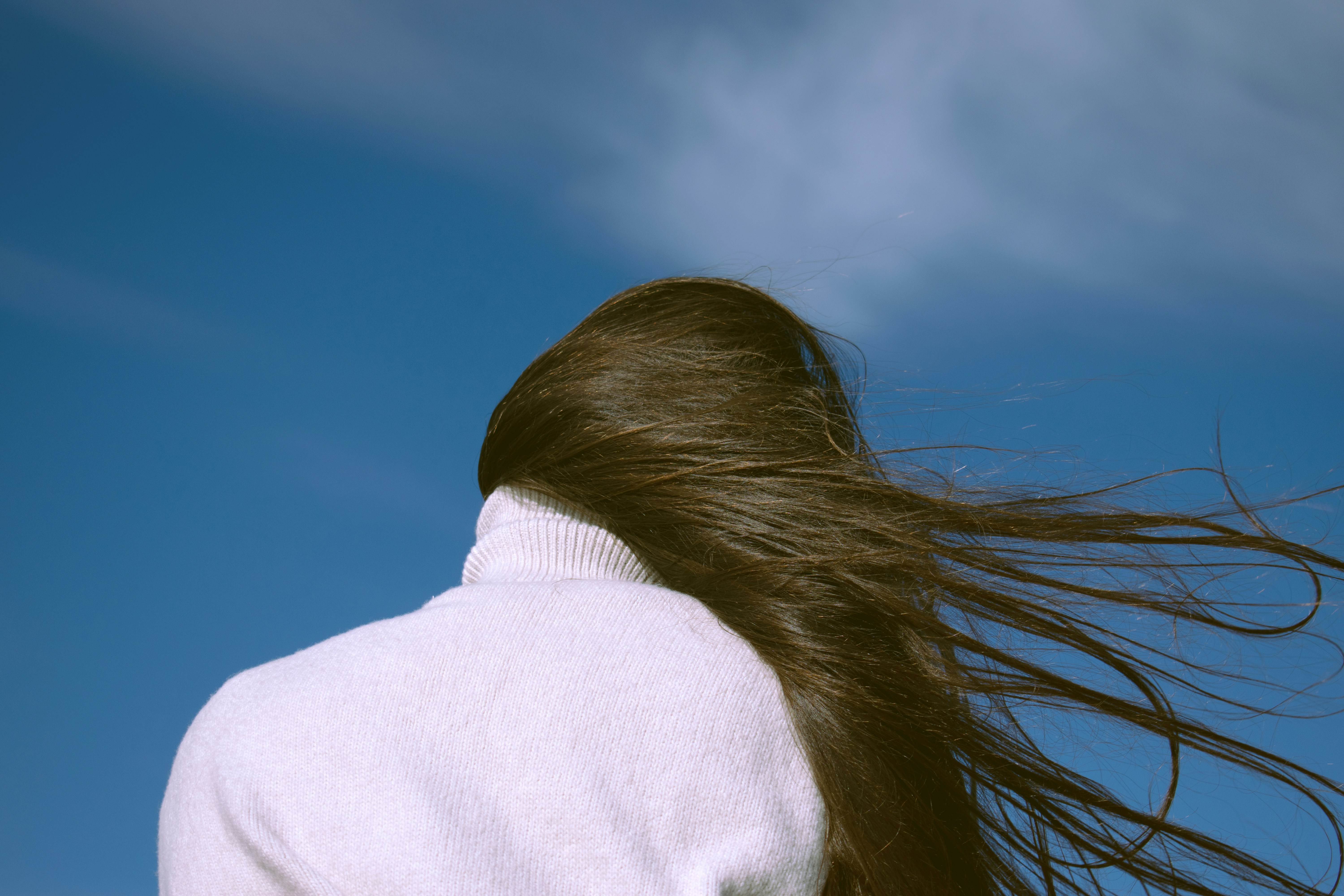 Long hair flowing in the breeze against a clear blue sky, creating a sense of freedom and tranquility.