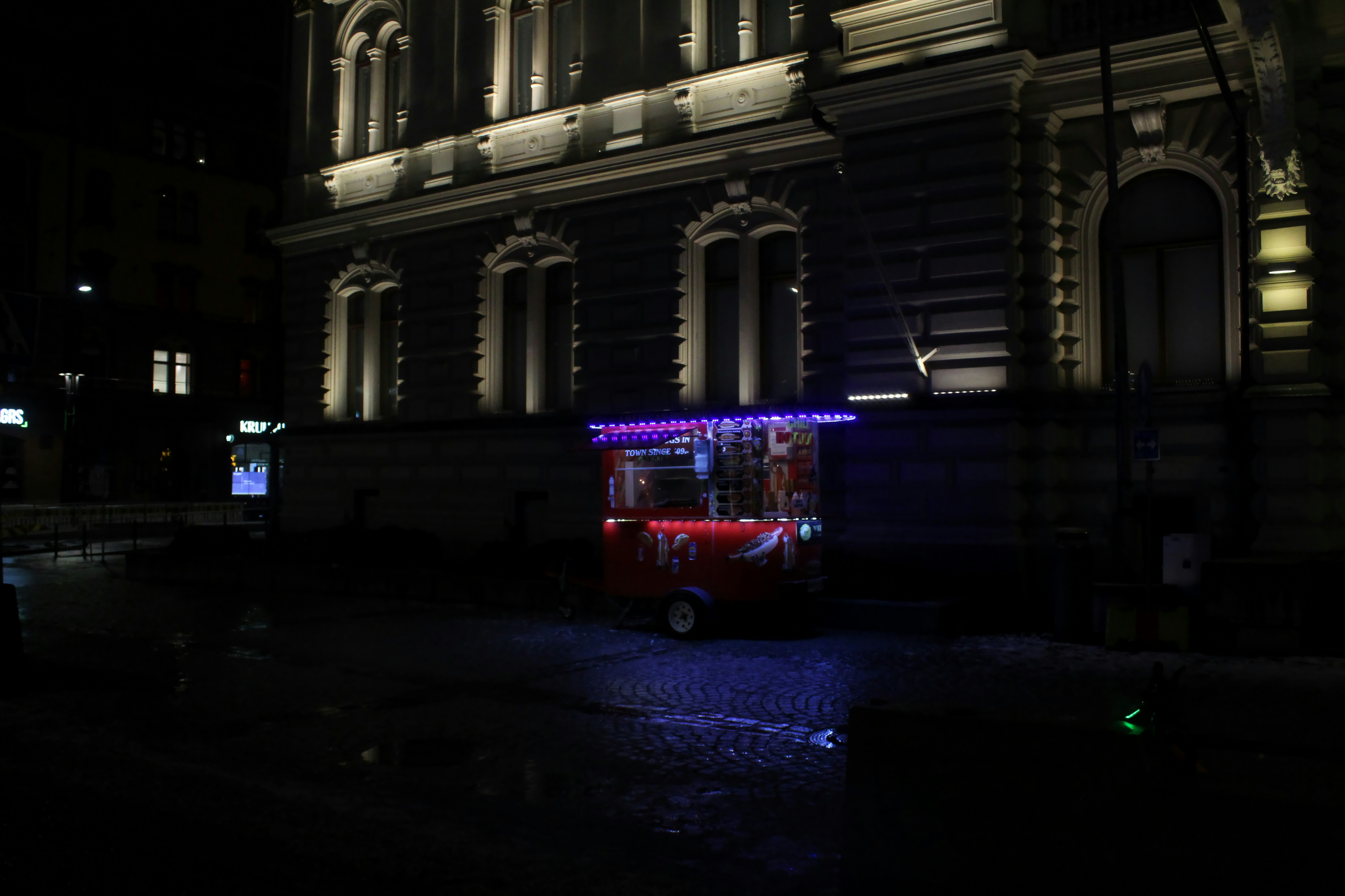 Red Night Cart Drenched in Neon Light Before a Historic Facade
