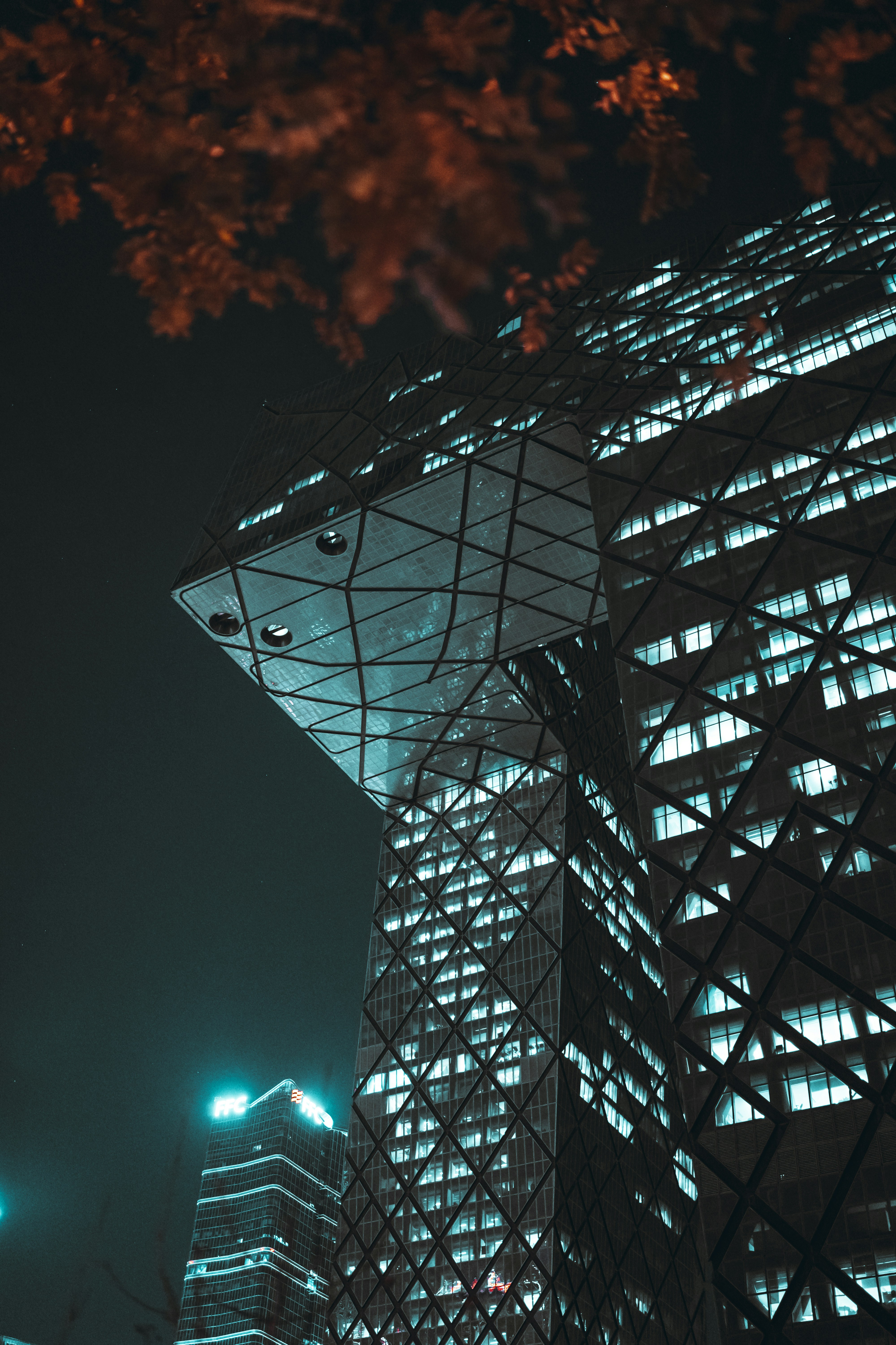 Modern skyscraper with illuminated geometric patterns against a night sky.