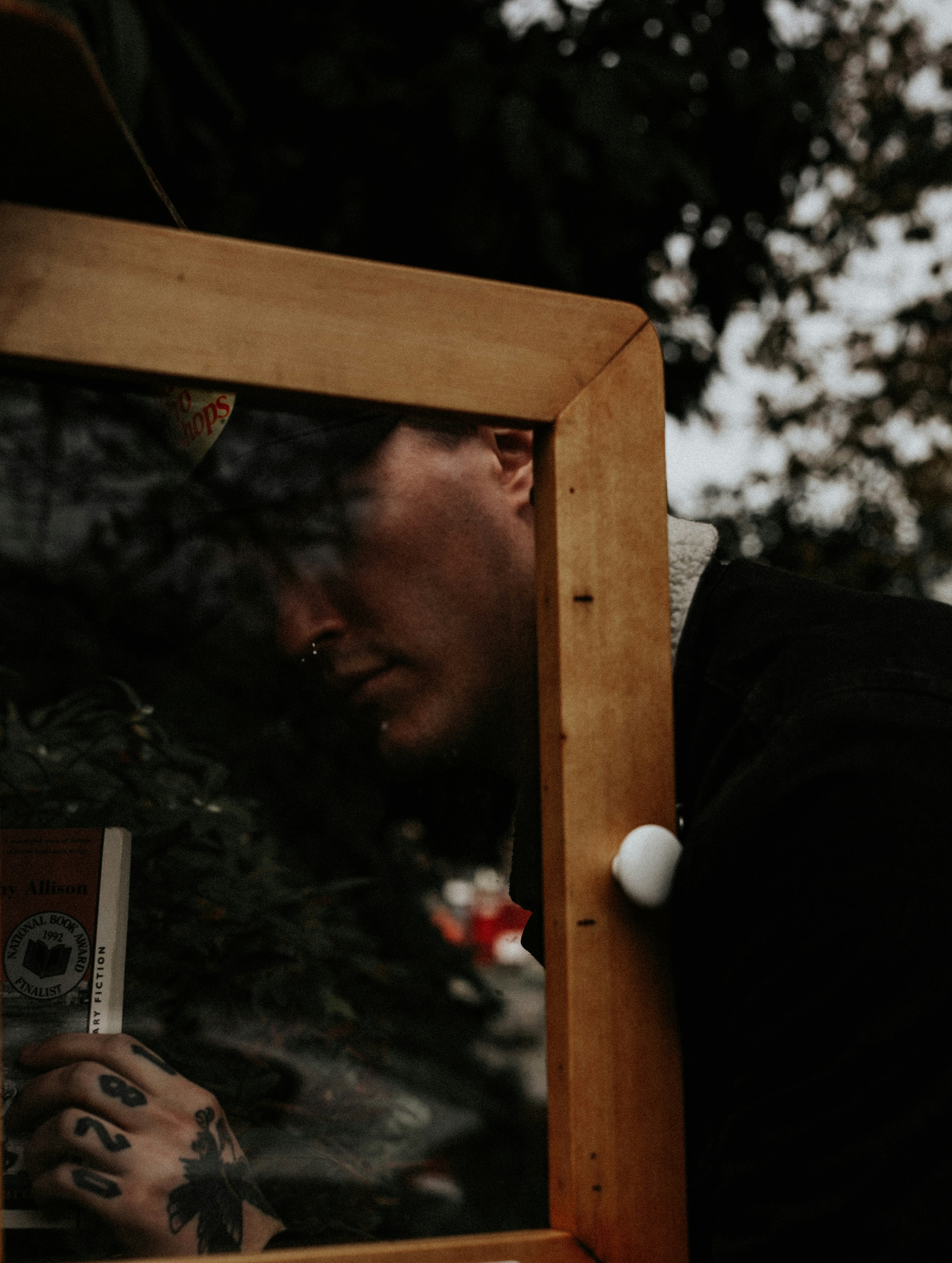 man holding a camera in a brown wooden frame