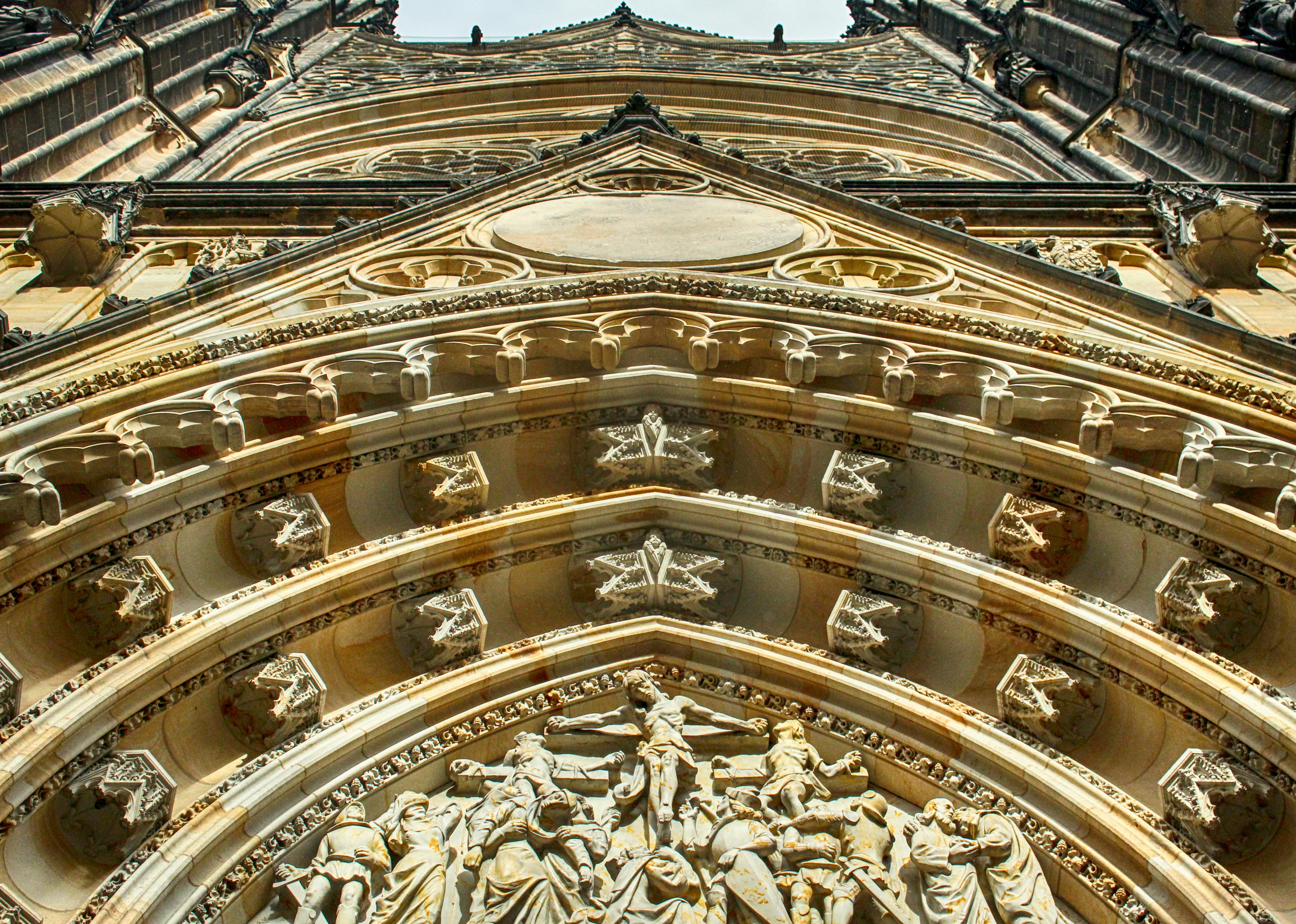 Intricate stone carvings and arches of a historic cathedral, showcasing detailed sculptures under a clear sky.