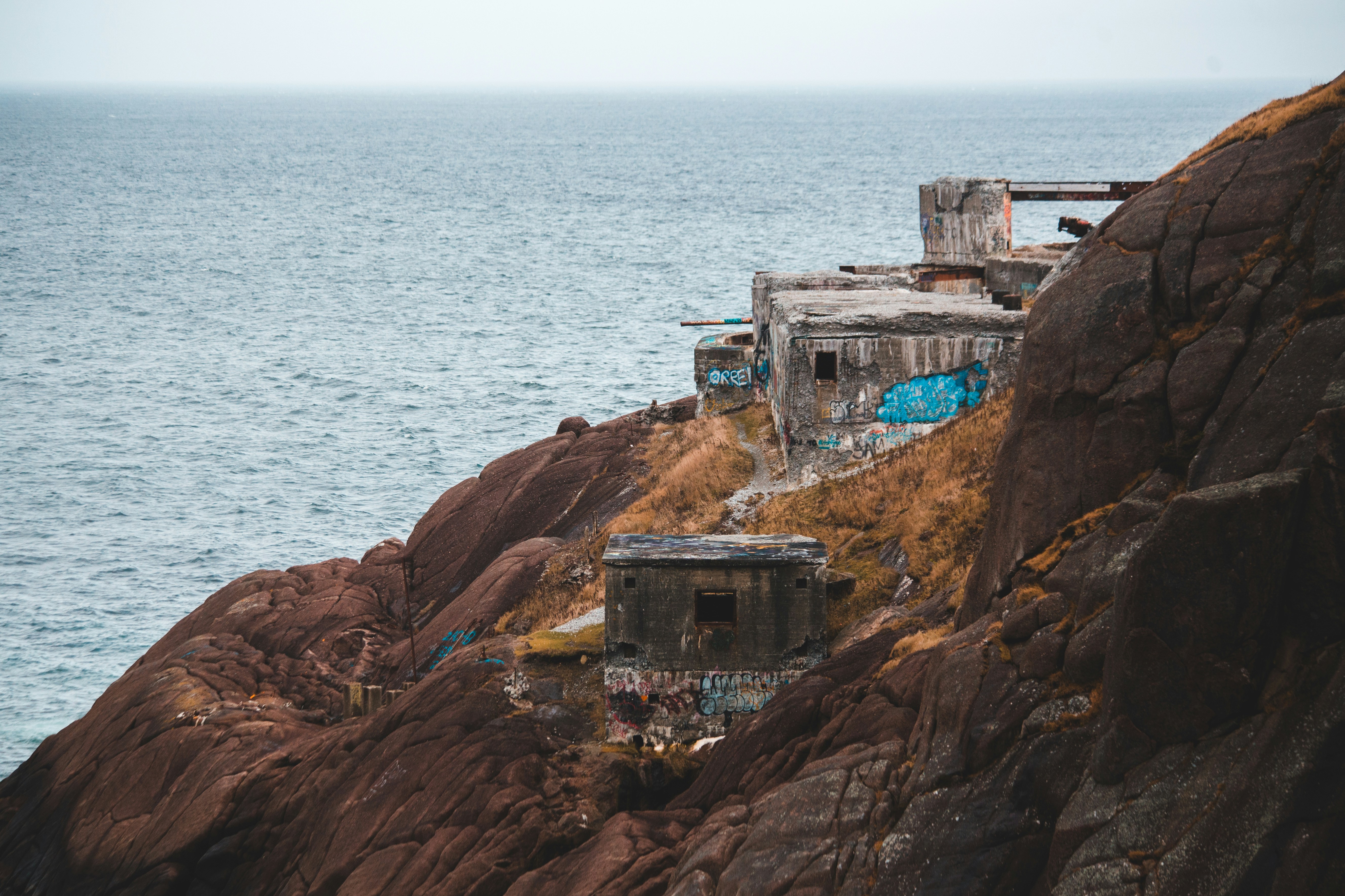 An old shack on a rocky cliff by the ocean photo – Free Building Image ...