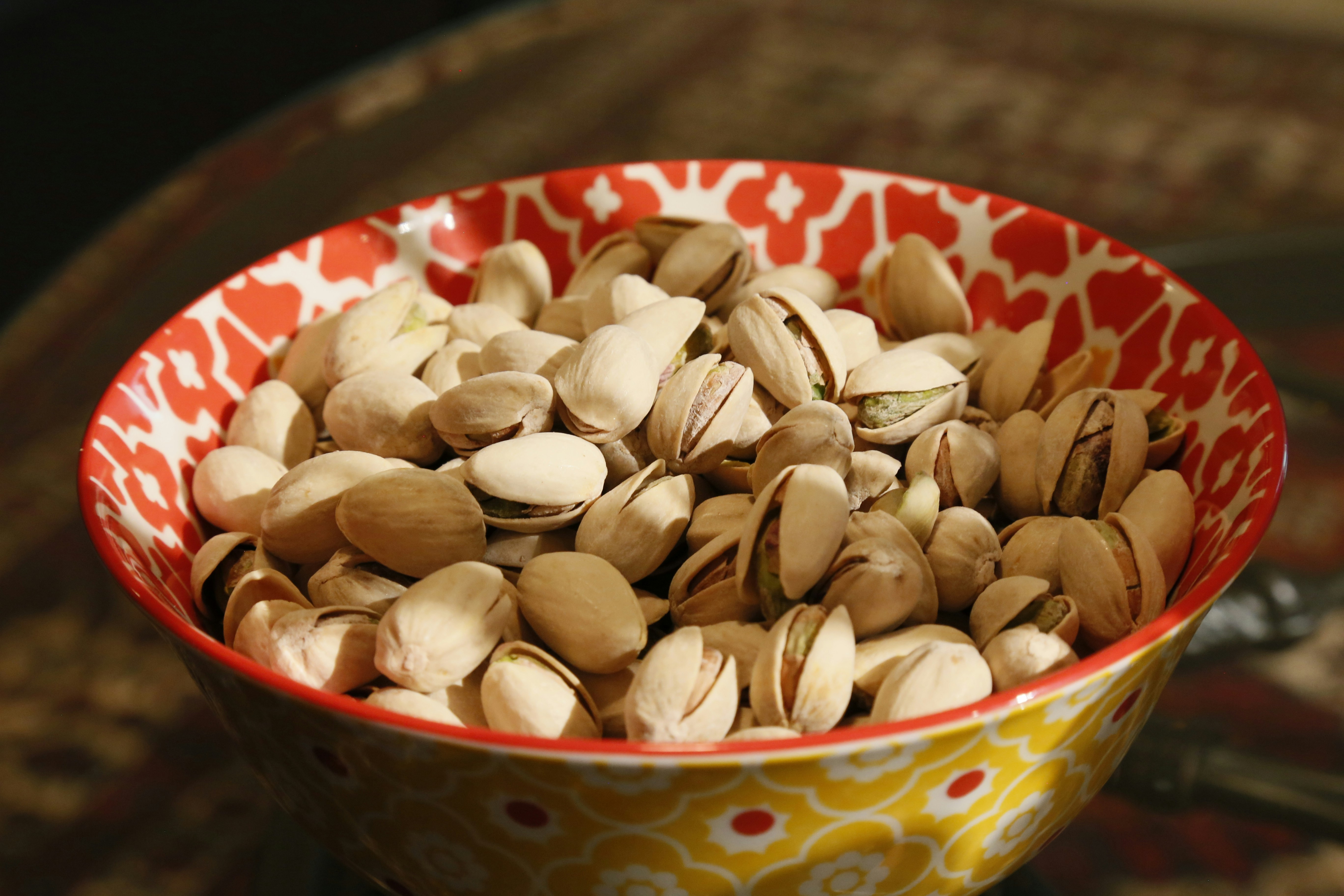 A vibrant bowl filled with pistachios, showcasing their unique textures and colors against a decorative background.