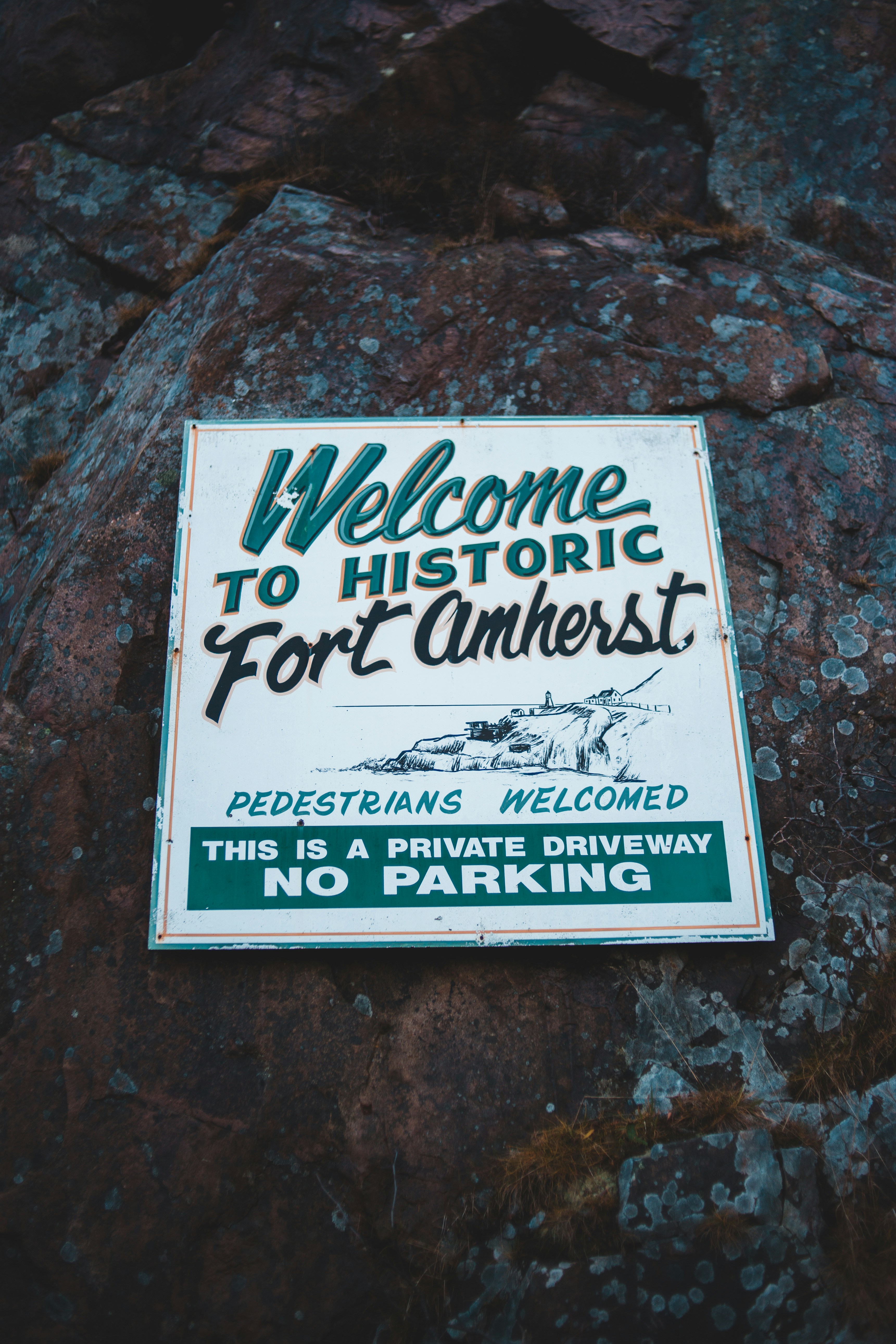 Welcome Sign Nestled in Mossy Rocks at Fort Amherst