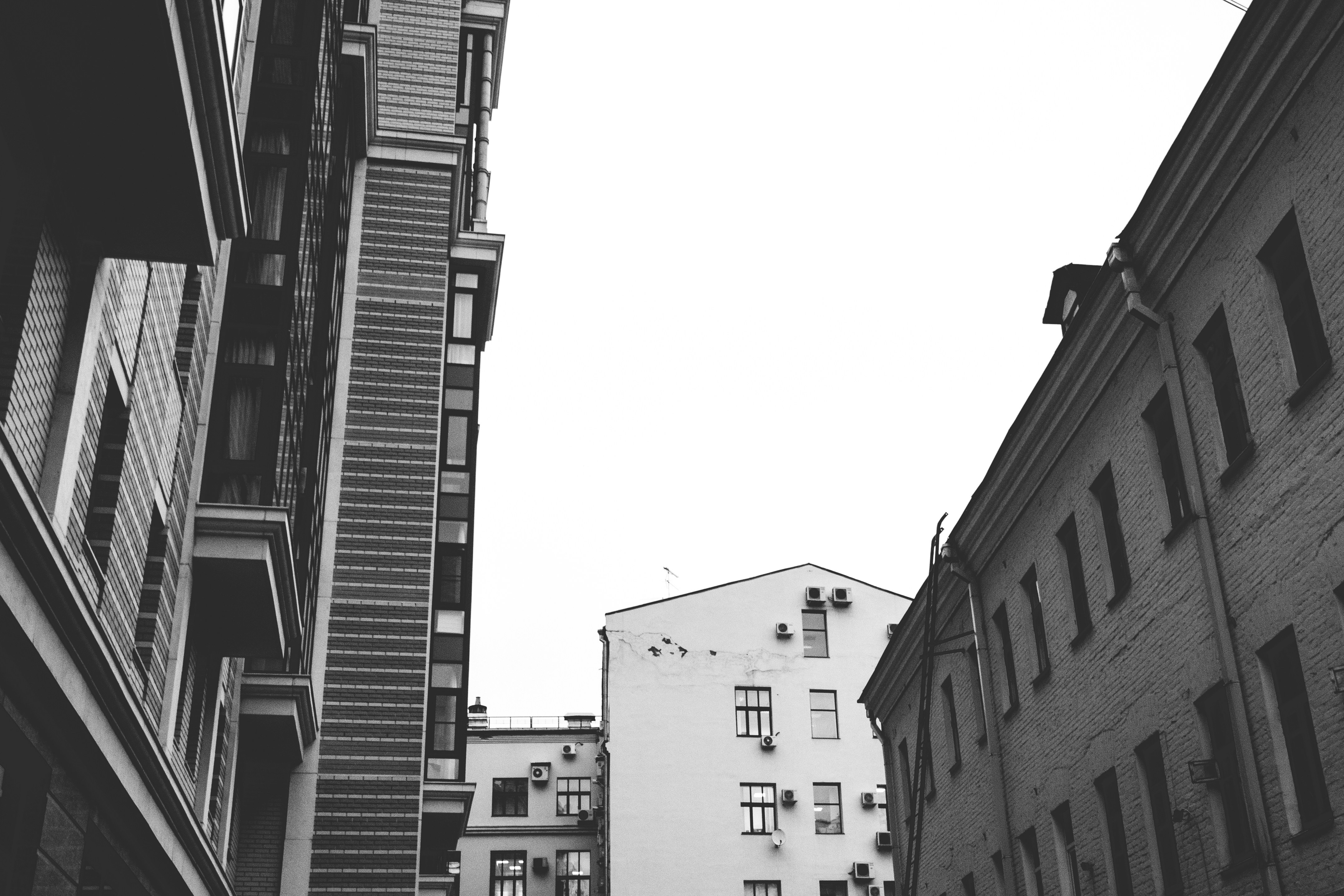 Monochrome view of contrasting architectural styles, showcasing a modern building adjacent to an older structure. The upward angle emphasizes the verticality of the scene.