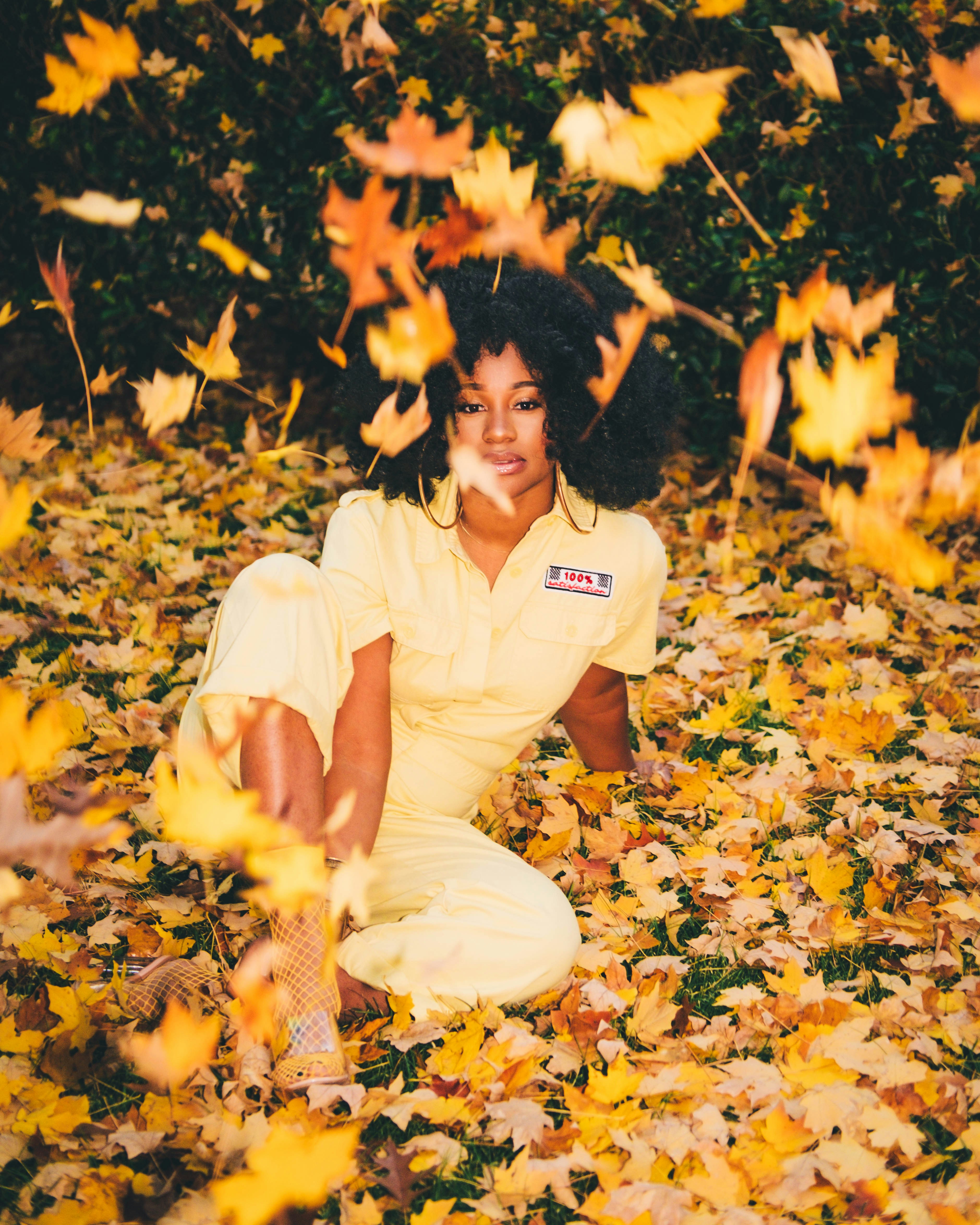 a woman sitting on the ground surrounded by leavesOsarugue Igbinoba