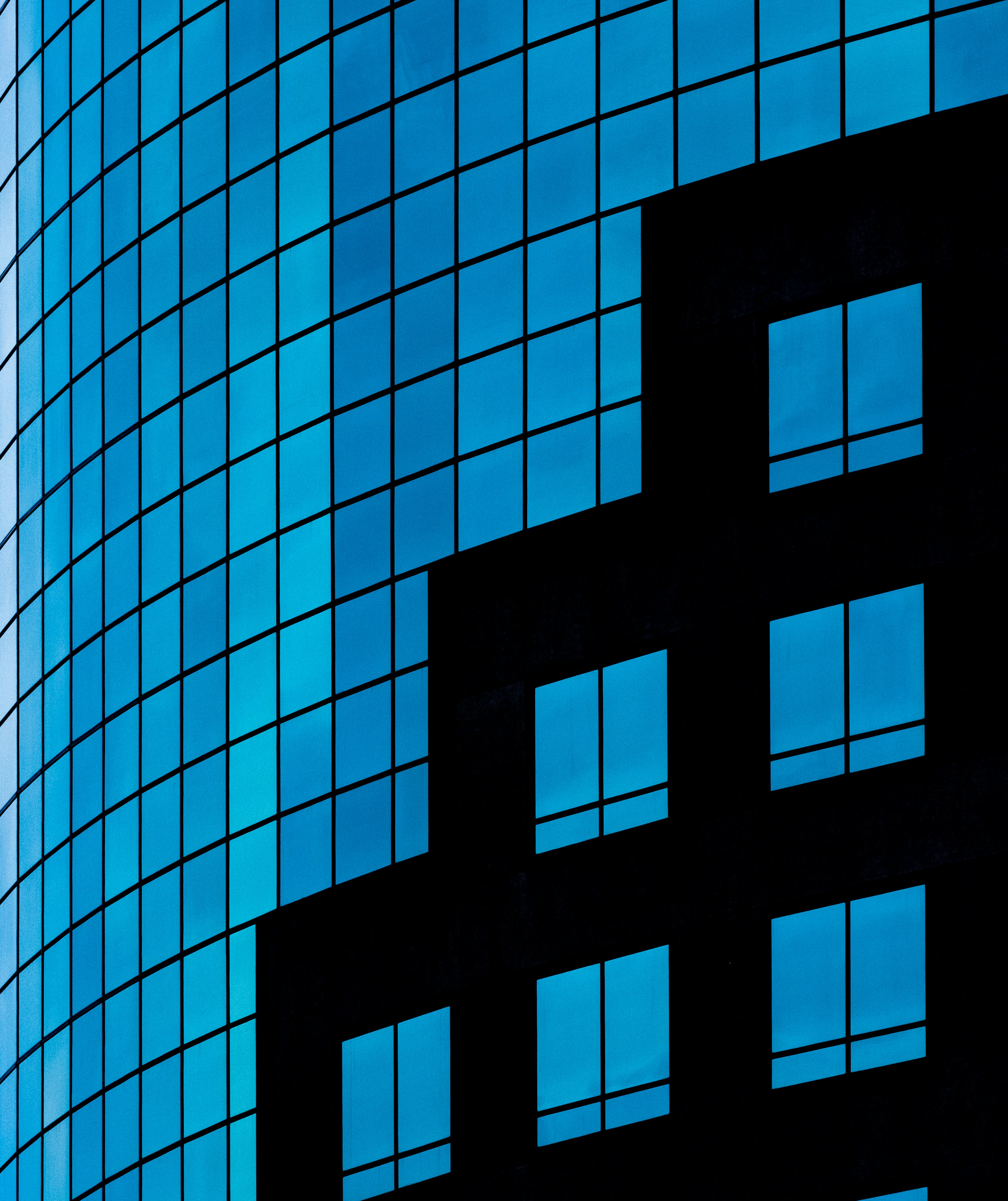 Glassy Facade, Cropped Geometry: Neon Blue Grid Over Shadowed Architecture