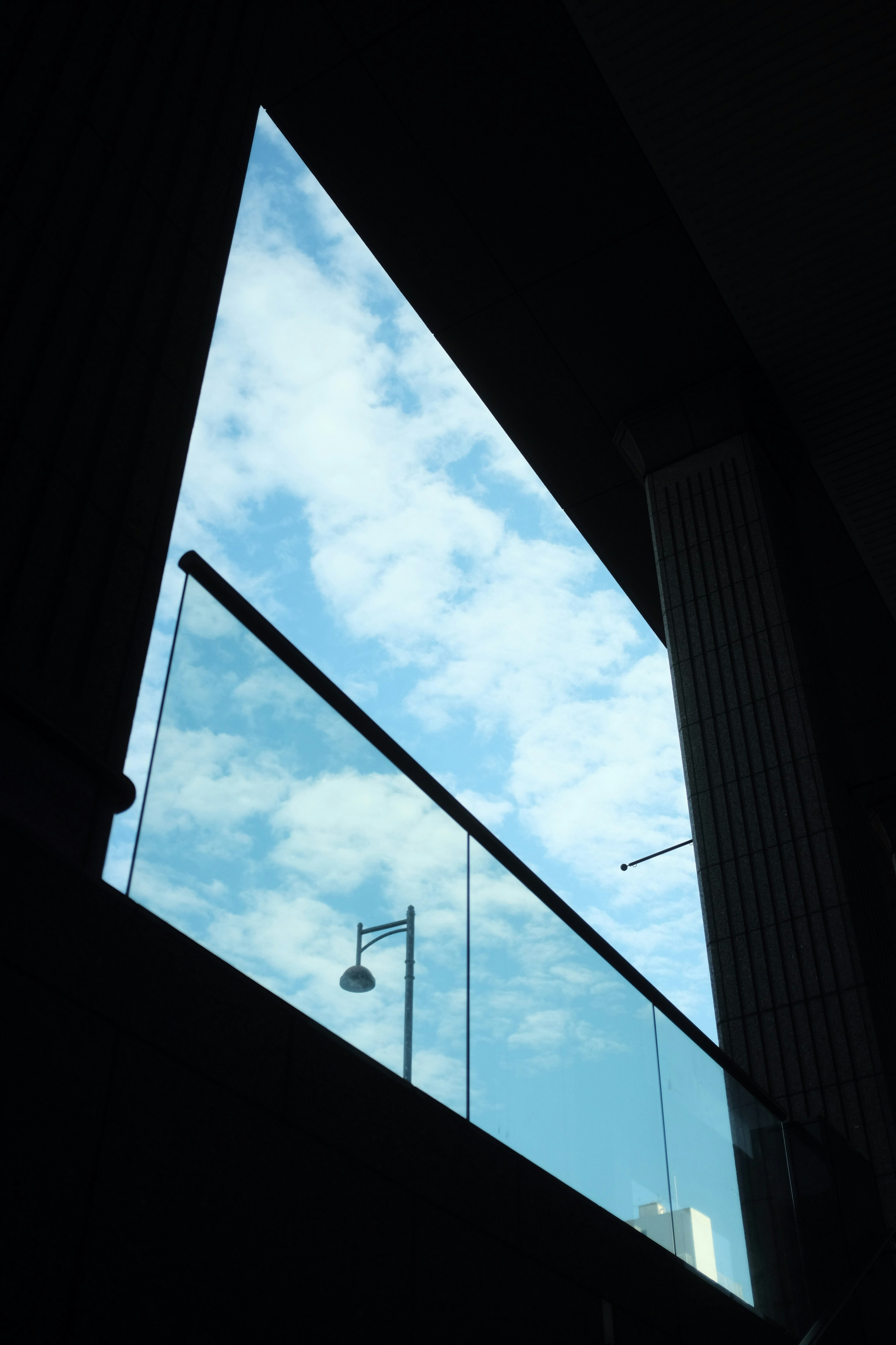 A geometric view of the sky through a large angular opening, framed by sleek architectural elements and a hint of urban lighting.