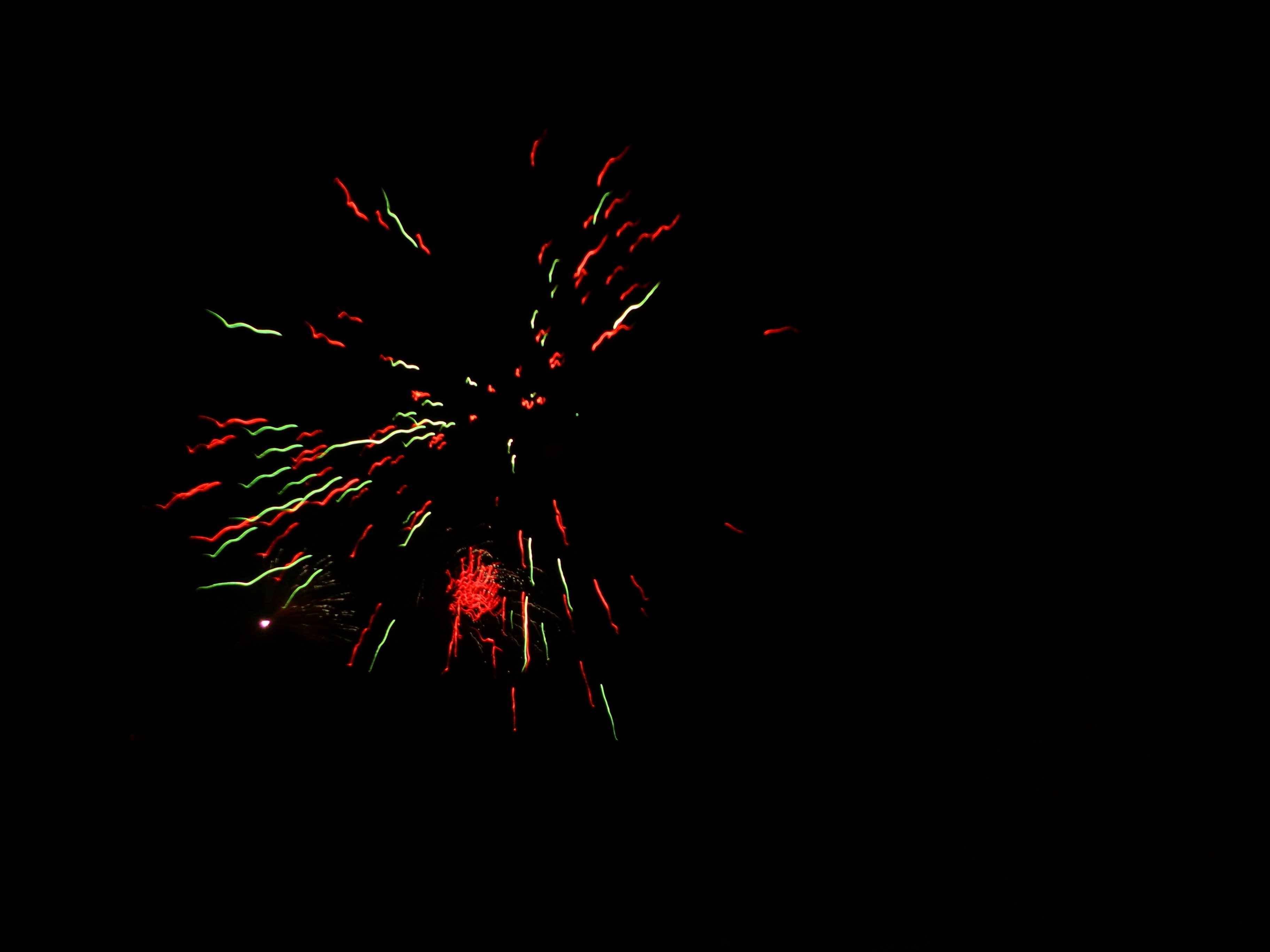 Fireworks bursting in a vibrant display of red and green against a dark sky.