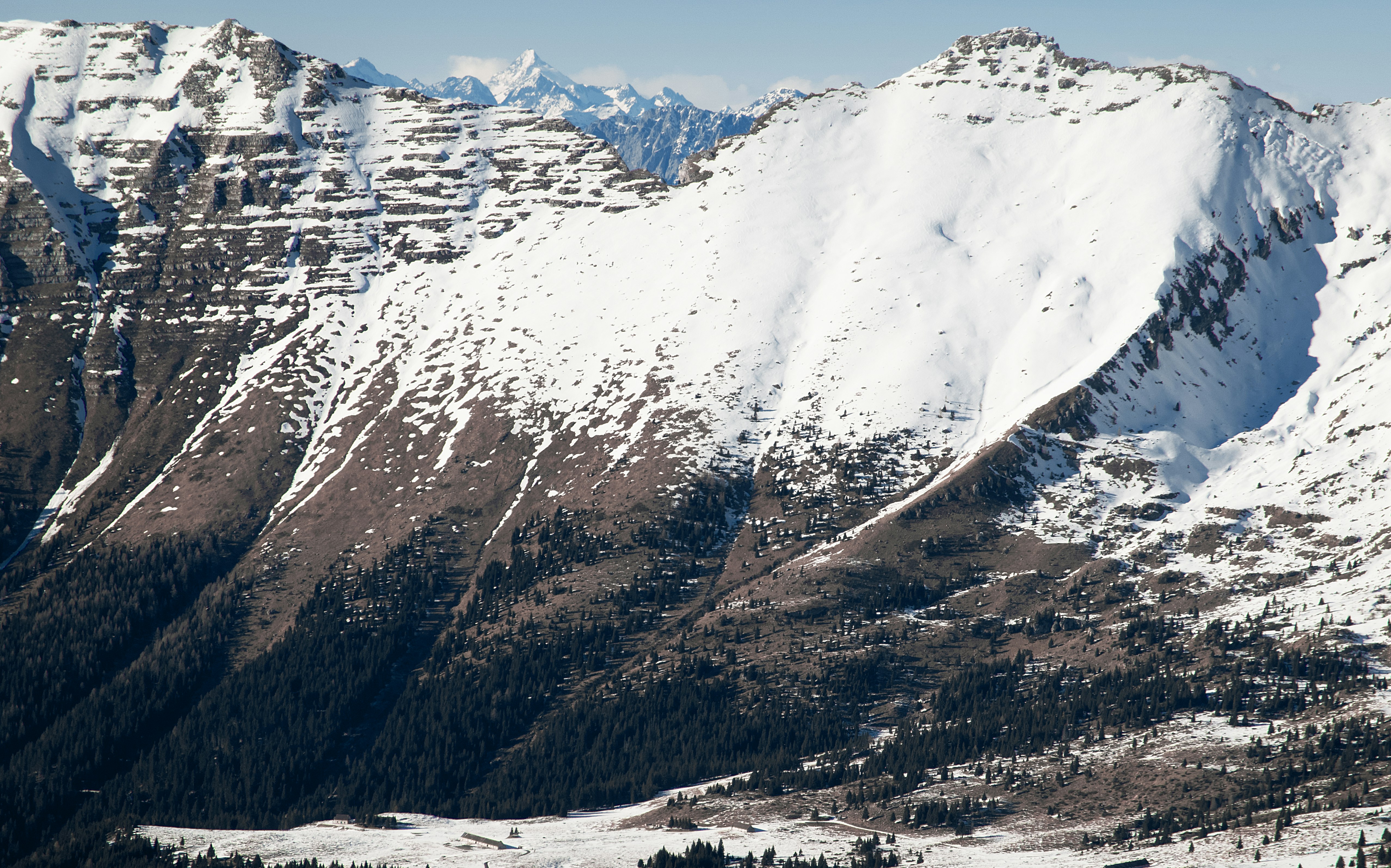 Snow-covered mountain range with rugged peaks and valleys, showcasing the stark contrast of winter's chill against the earthy tones below.