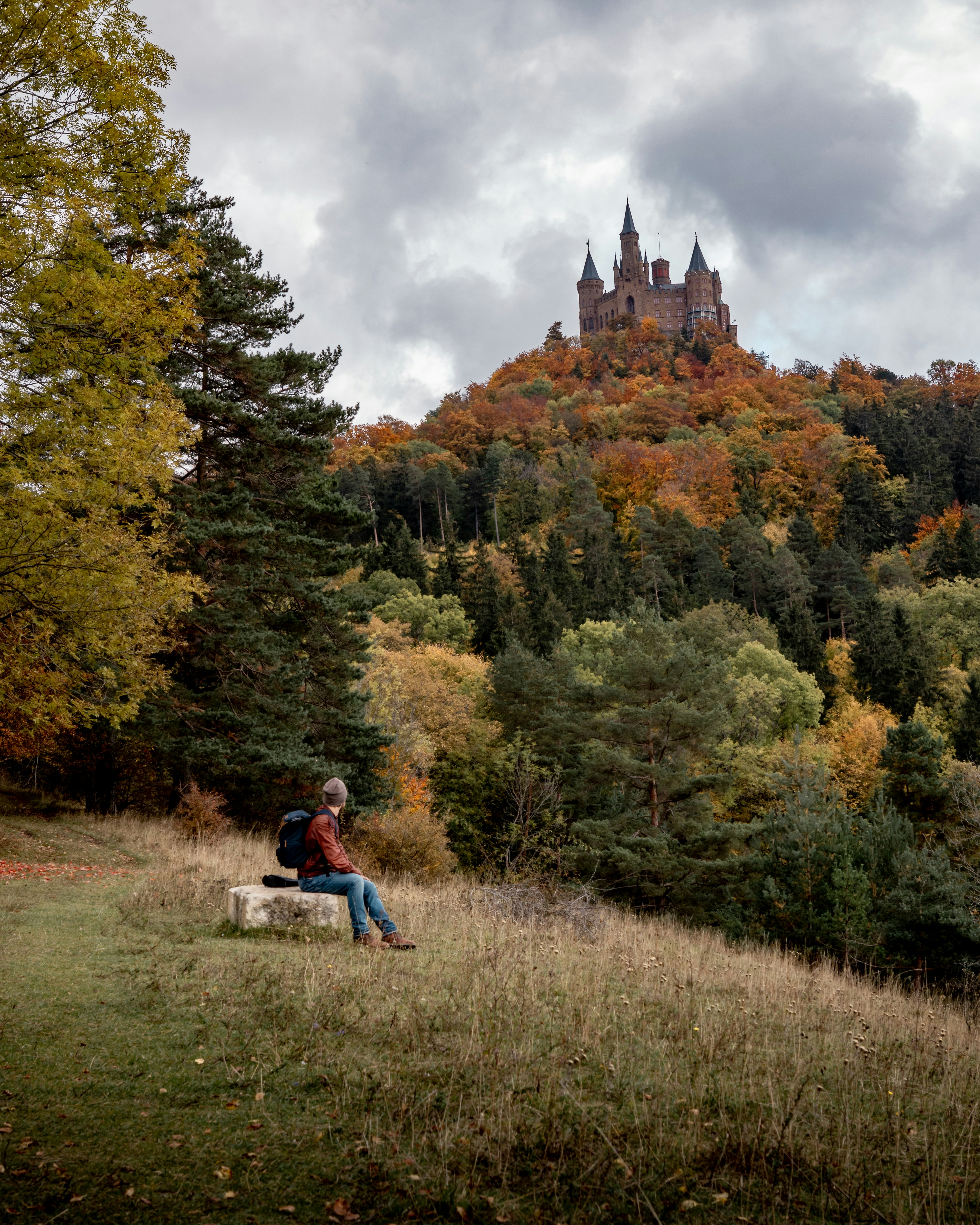 Autumn Crown: A Lone Hiker Seated Beneath a Hilltop Castle